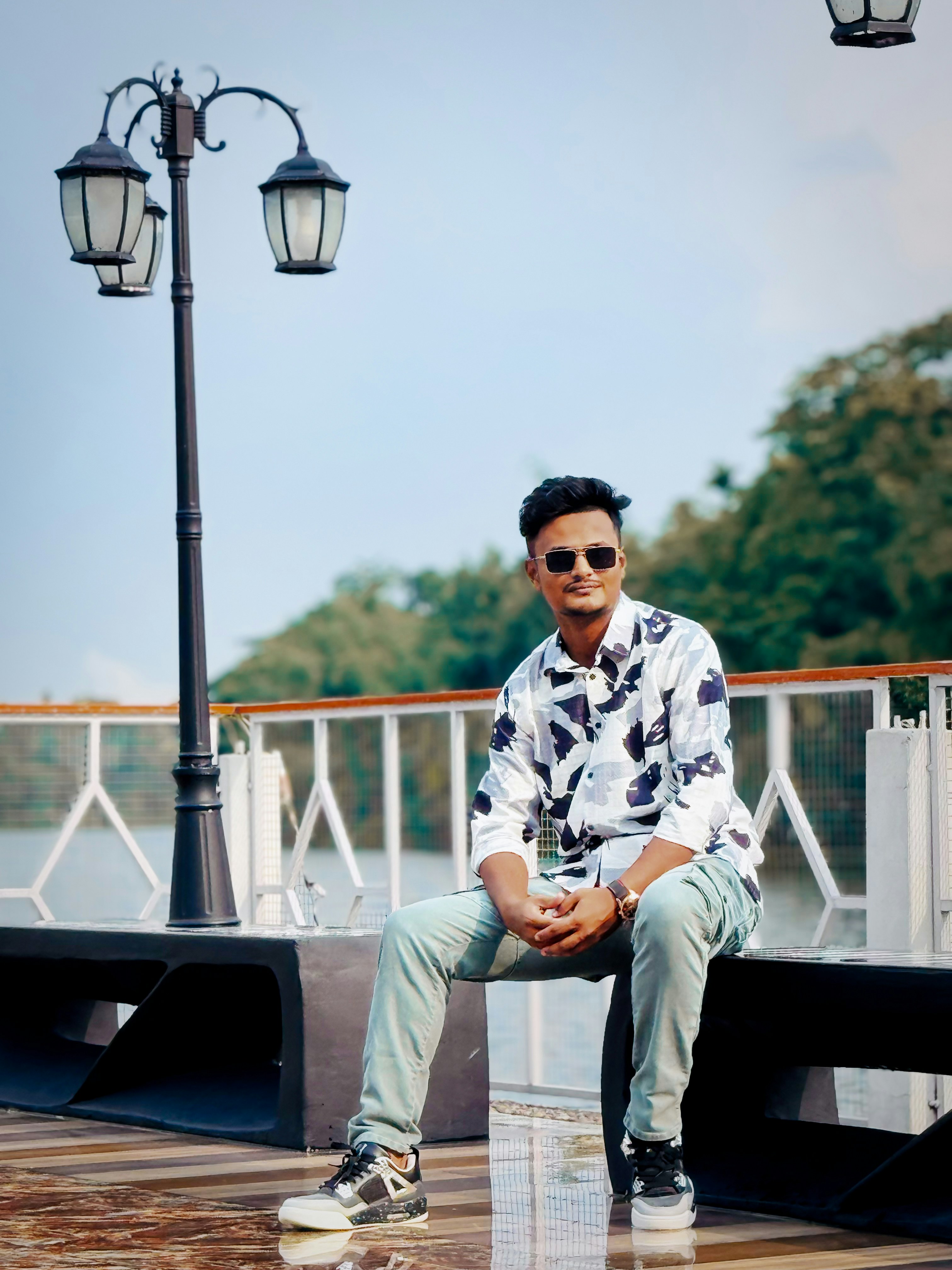Young man sitting on a bench with a street lamp.