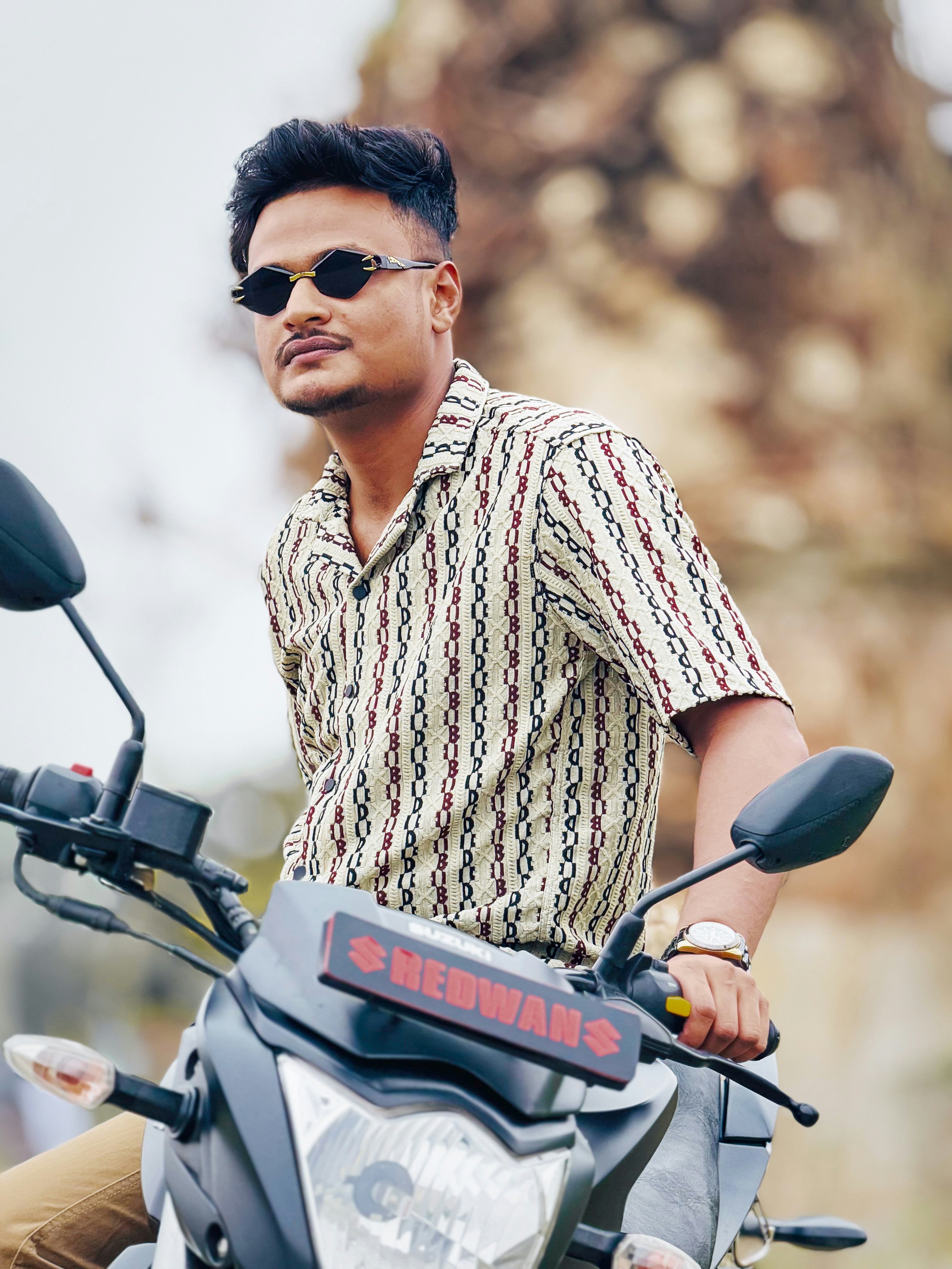 Styled Rider: Charcoal Sunglasses, Patterned Shirt, and a Regal Stance on the Bike
