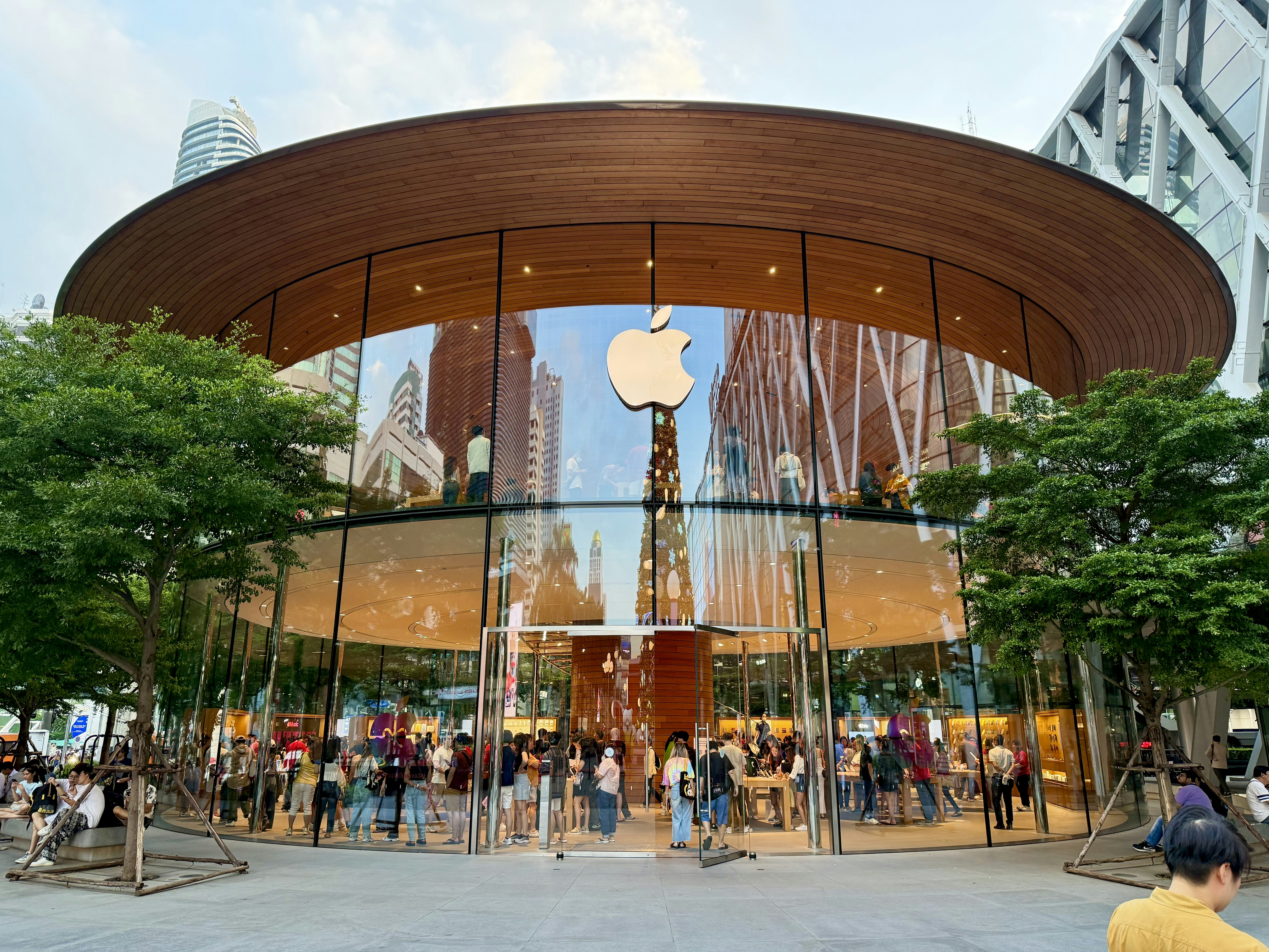 A striking circular glass structure stands at the heart of a bustling city center.