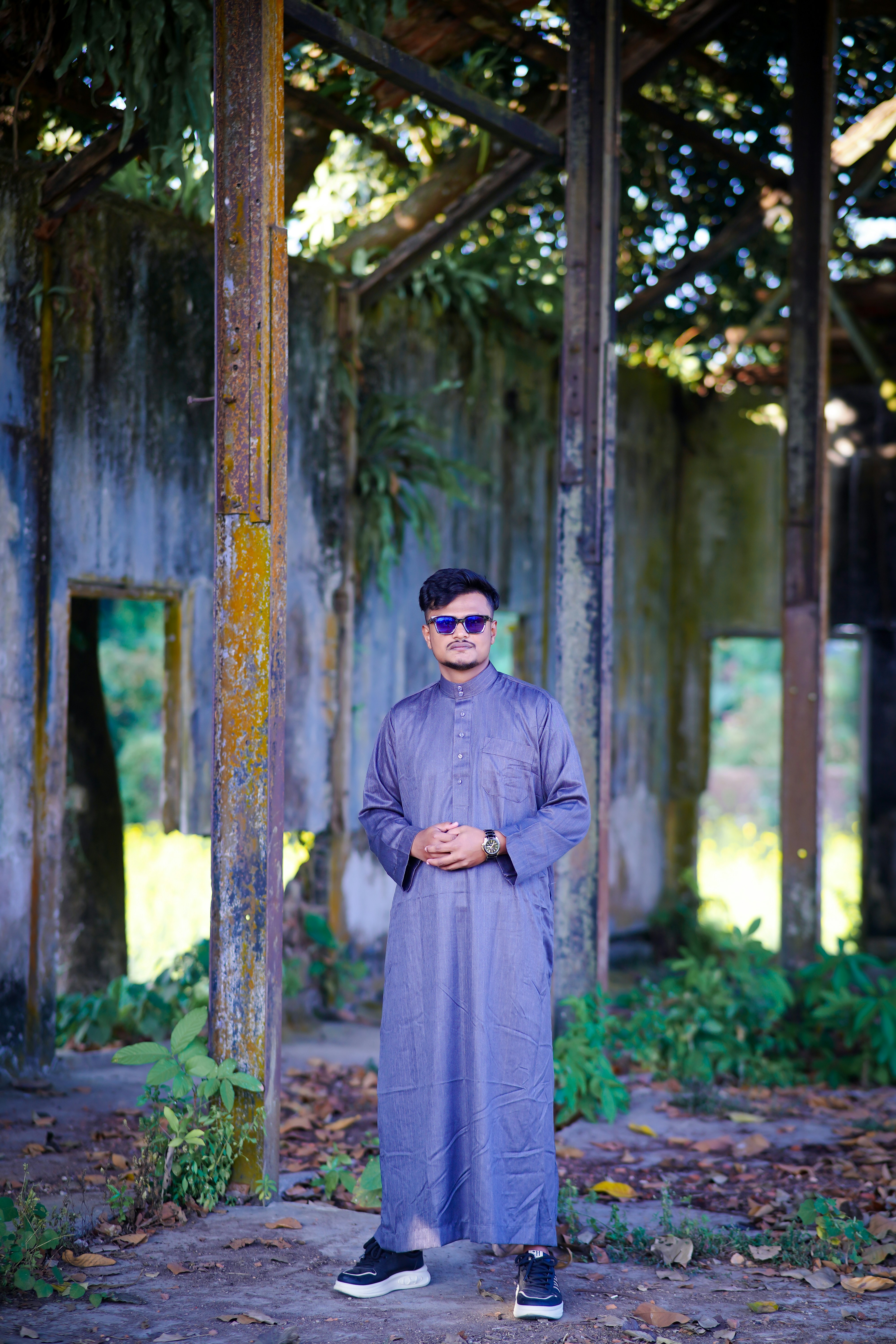 Man in a blue kurta among mossy pillars under open roof