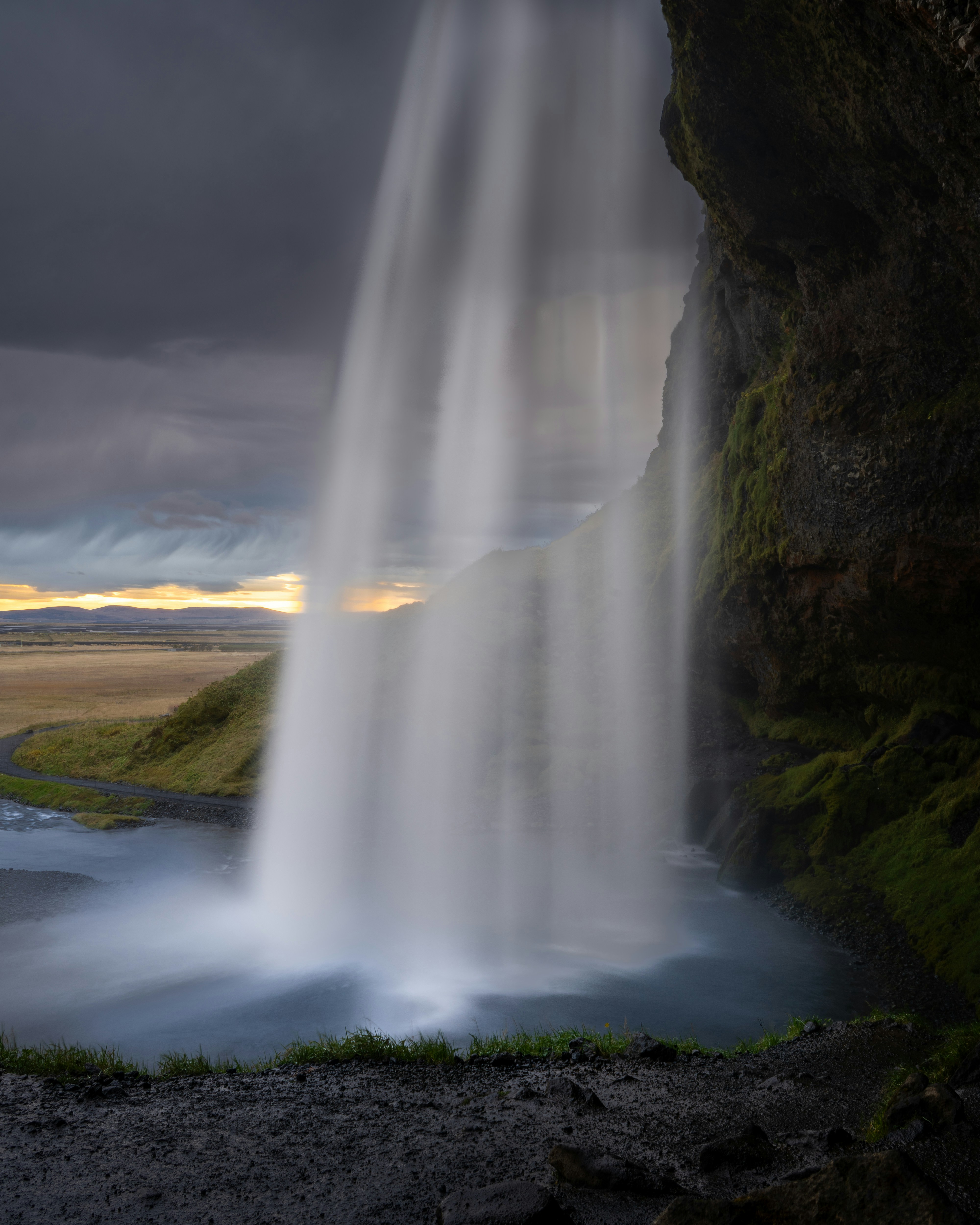 Graceful Veil: A waterfall carved into a mossy cliff at dusk
