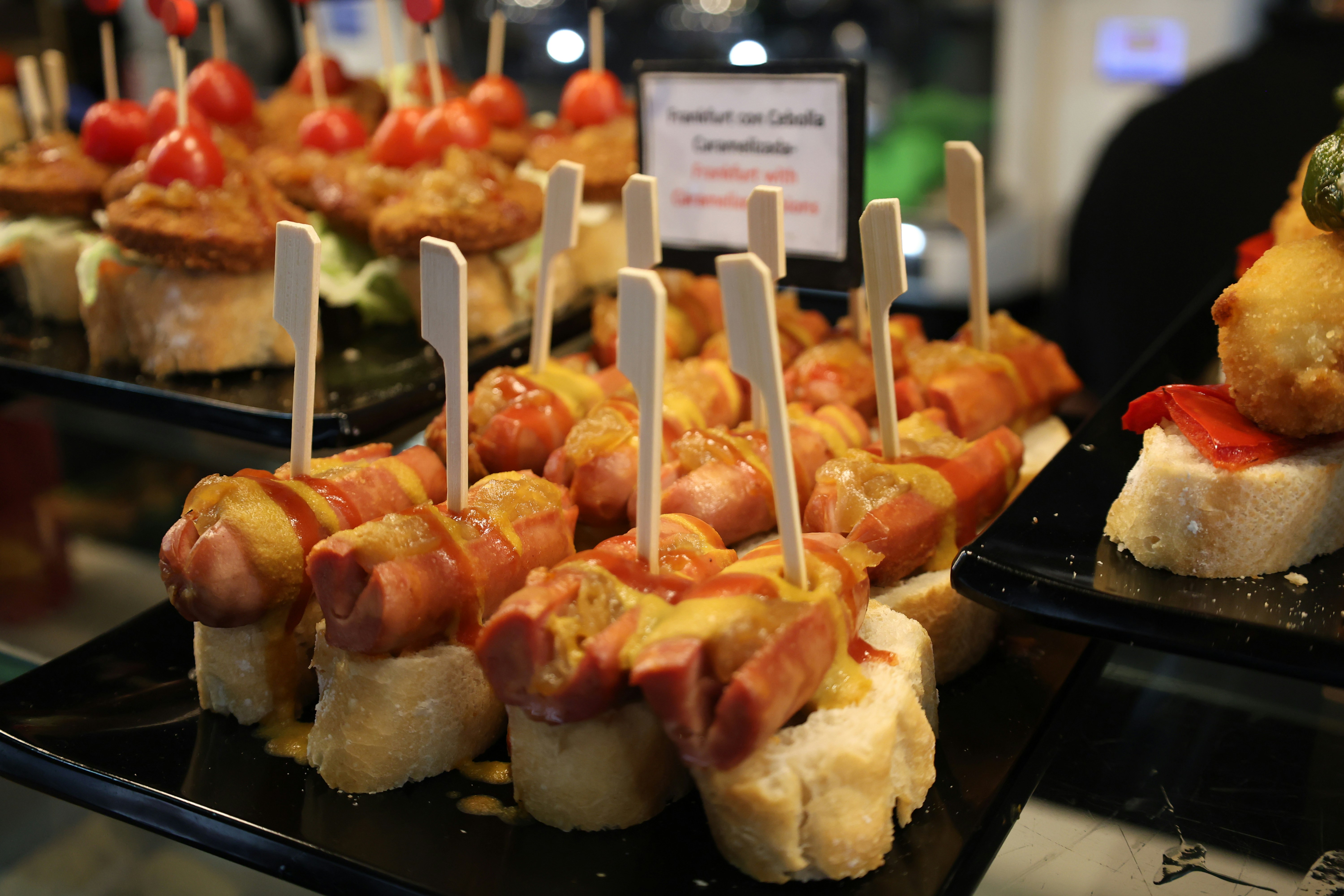 Small sausages with mustard on bread, served as appetizers.