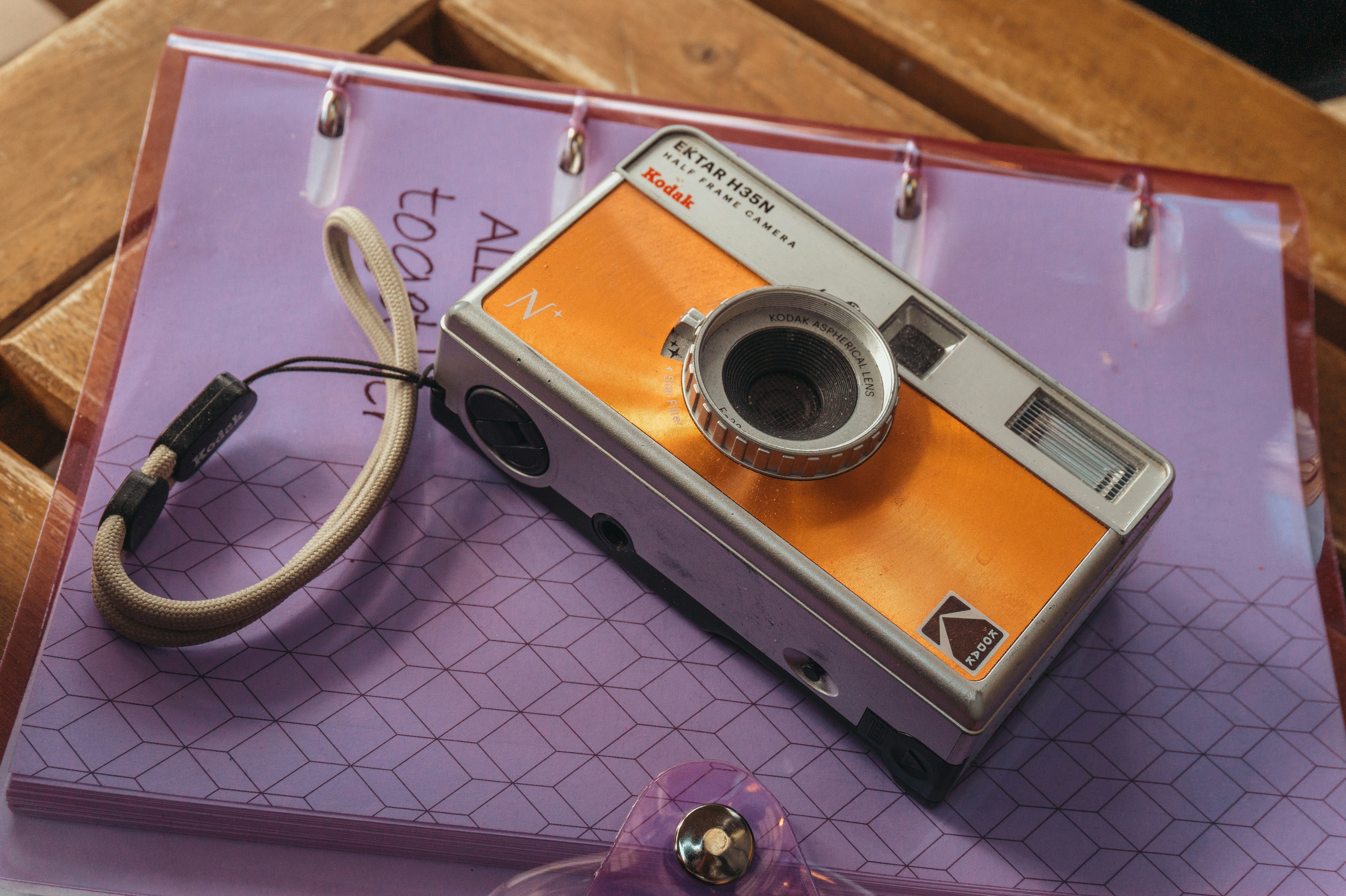 Orange Retro: A Compact Scene of a Vintage Point-and-Shoot on a Lavender Notebook