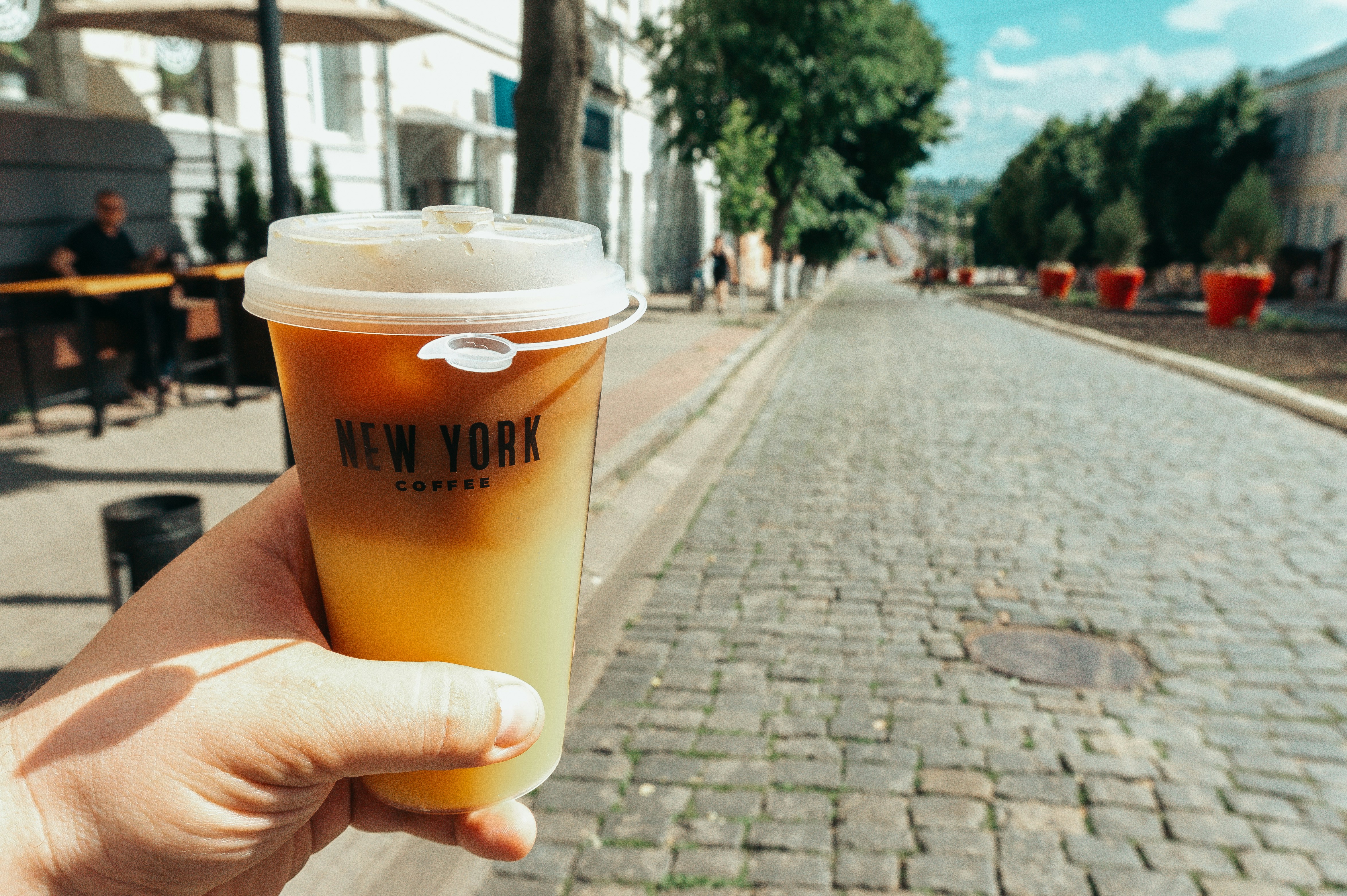 Handheld Coffee on a Cobblestone Street