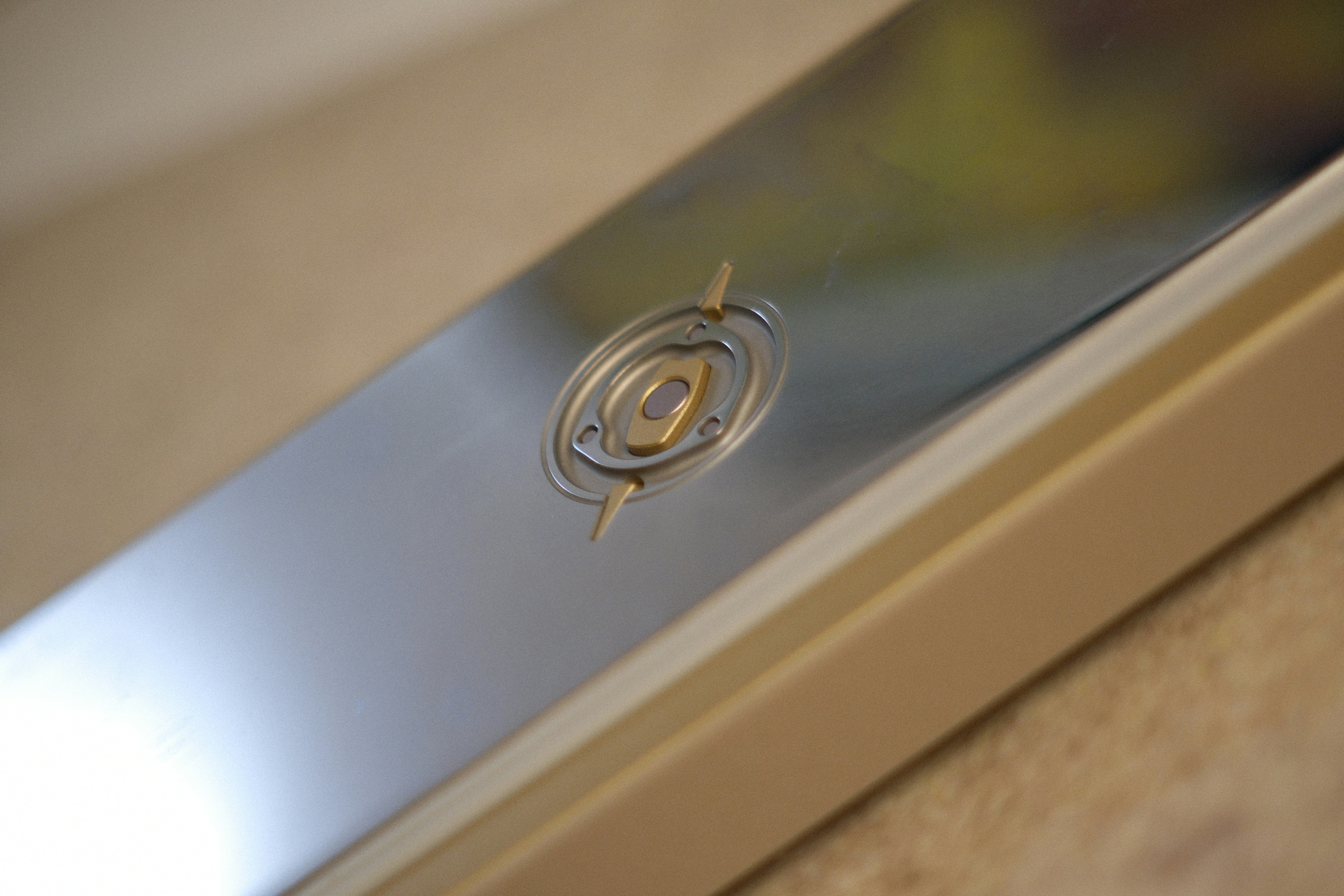 Shiny metallic strip with a golden embossed circular emblem.