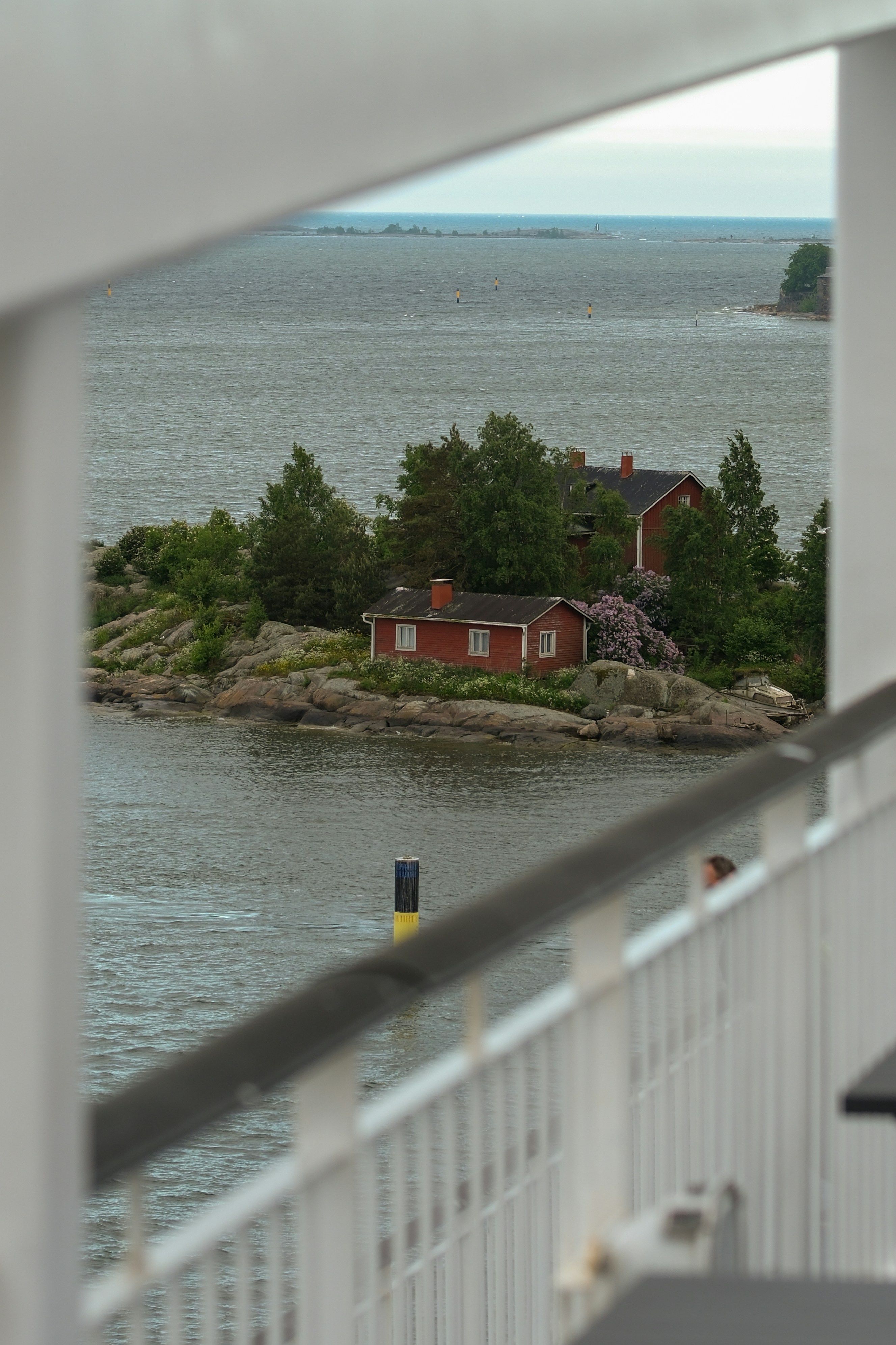 Red Cabin on a Quiet Island Framed by Balcony Rails