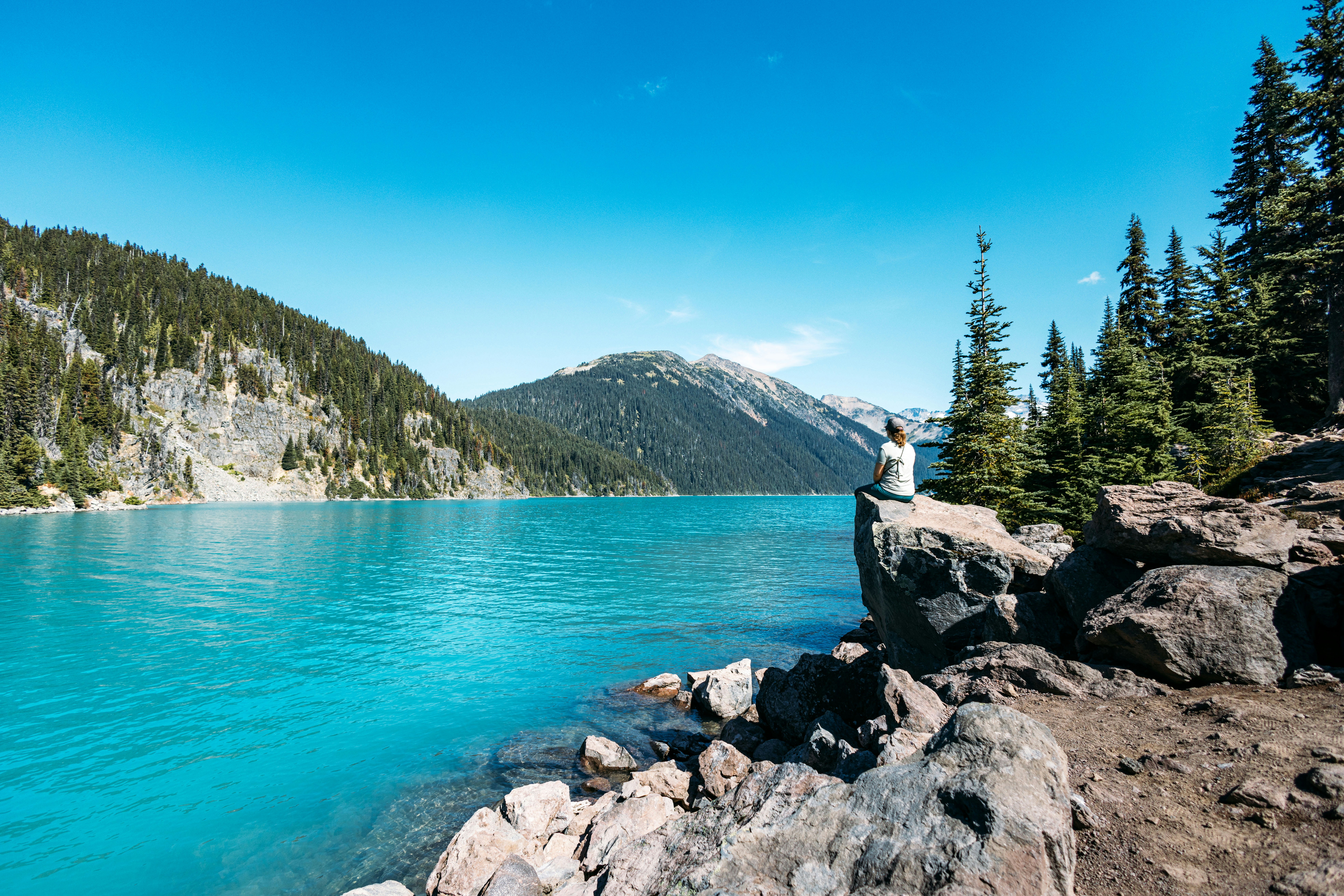 Solitary figure at the edge of turquoise alpine waters