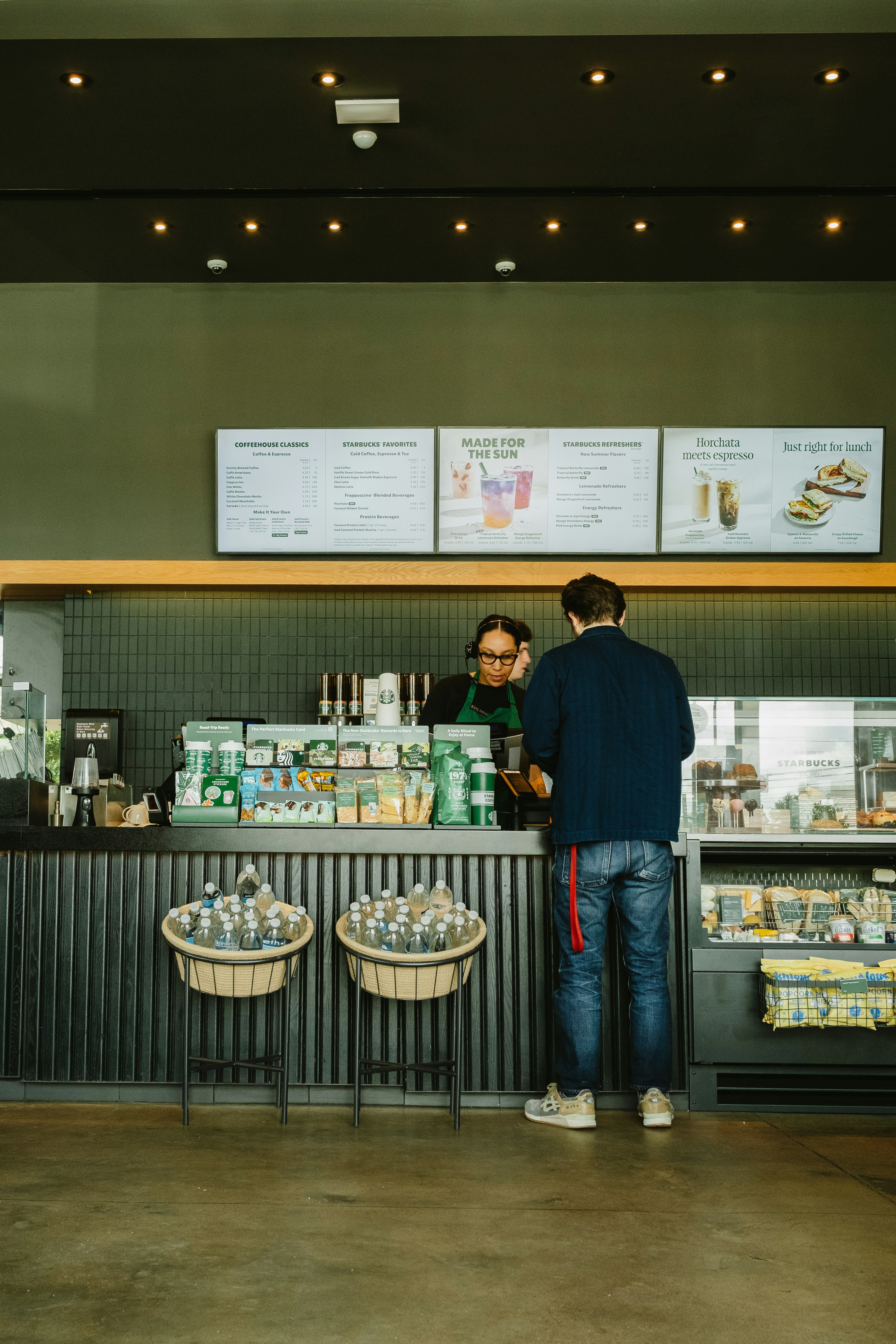 Customer at coffee shop counter ordering from barista.