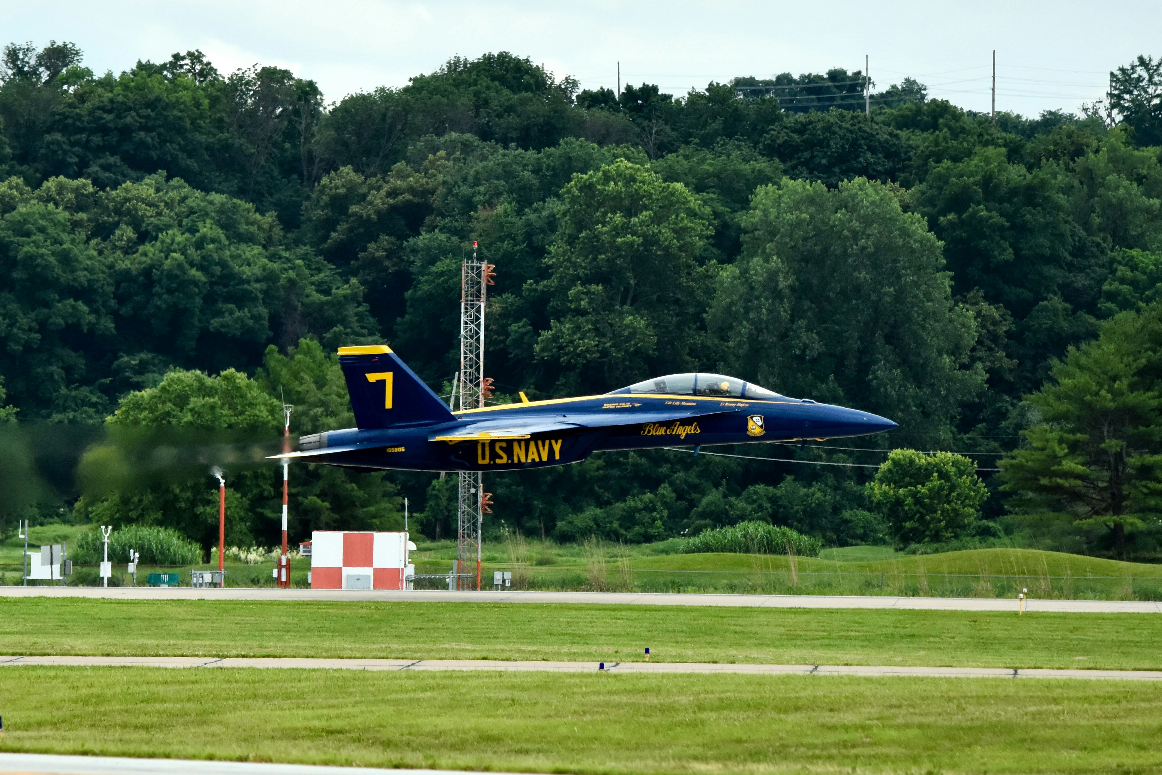 Blue angels jet flying low over a runway.