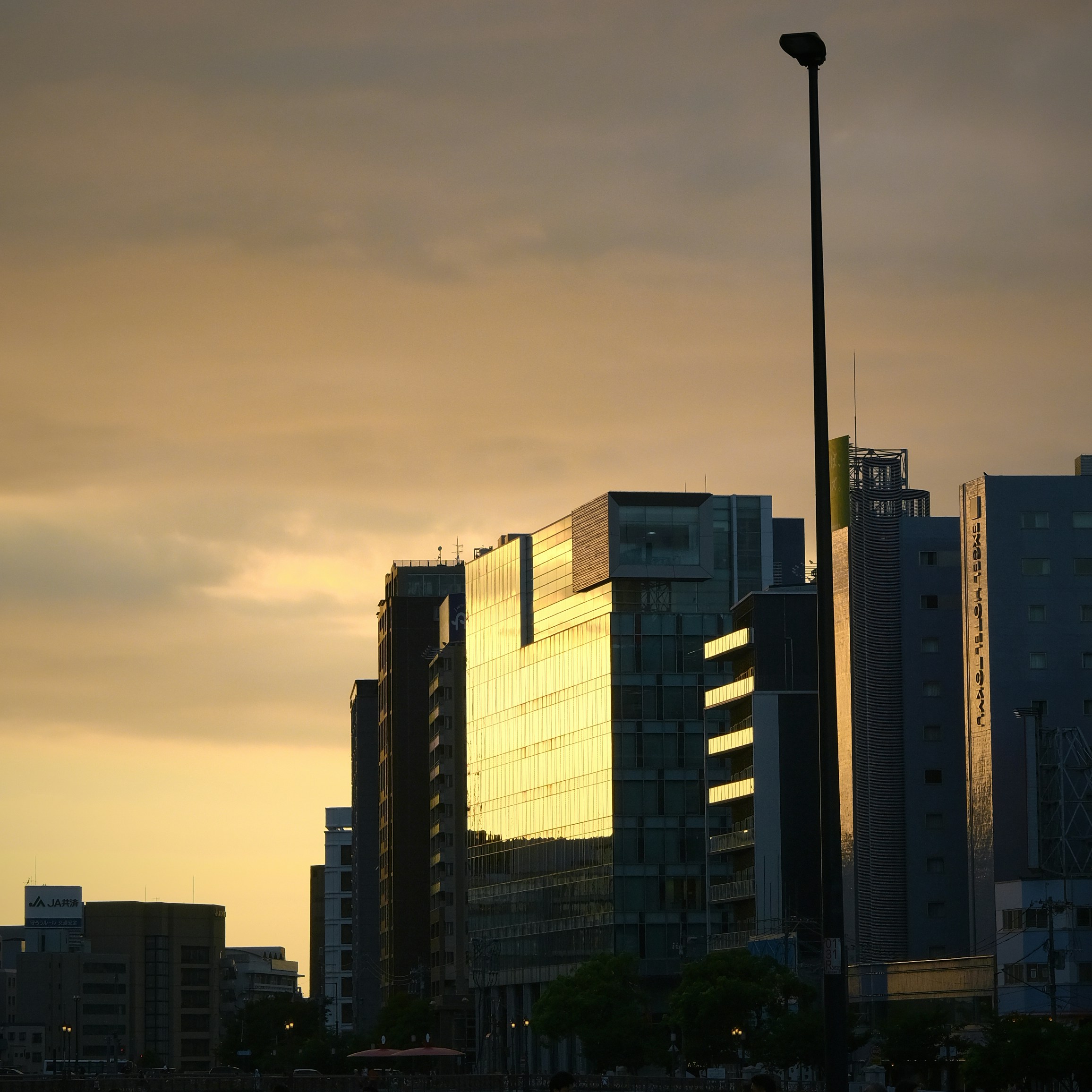 Sunlit Glass Coronation: Evening Facades Against a Quiet Horizon