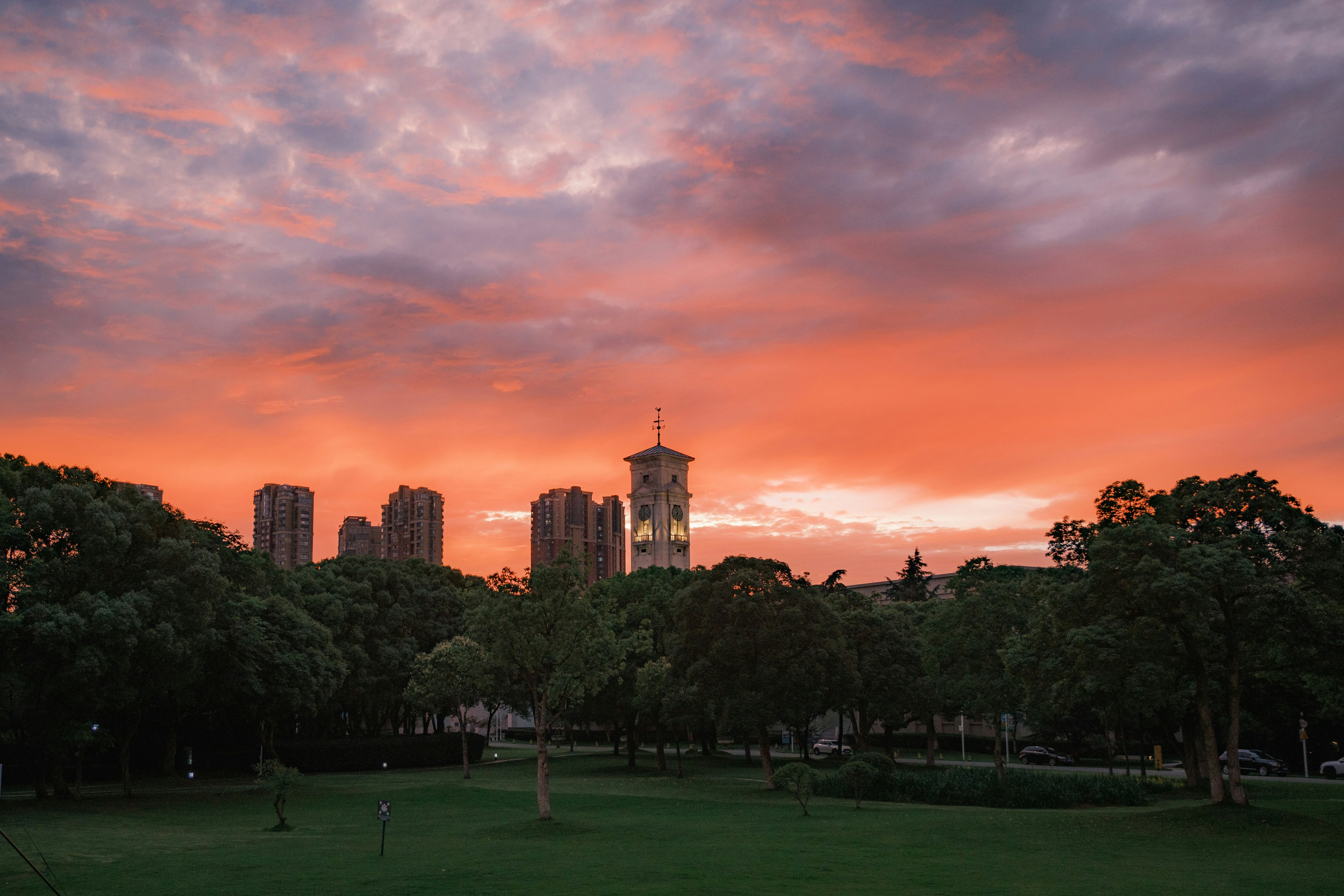 A vibrant orange and purple sunset over a city park.