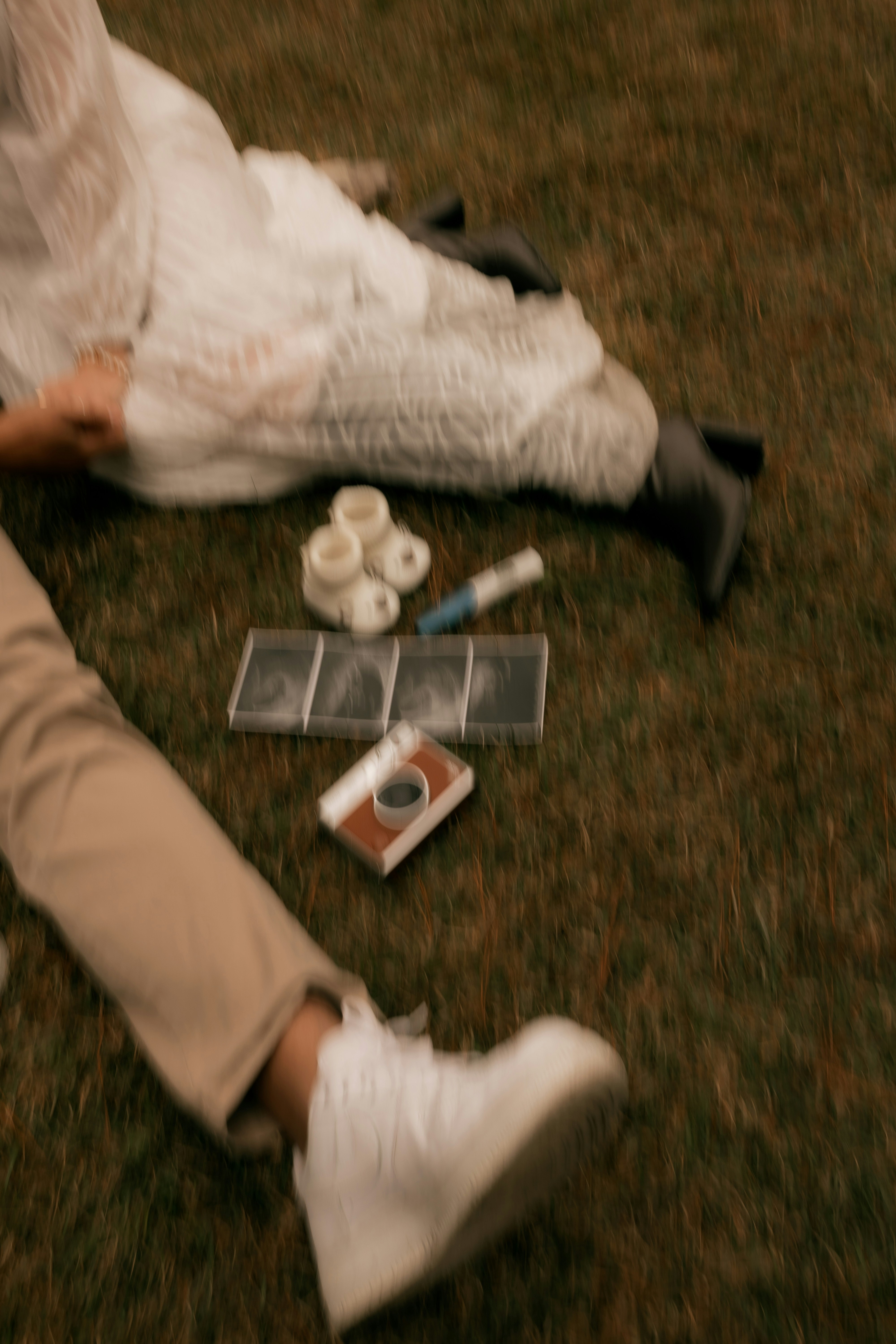 Two people relaxing on grass with craft supplies.