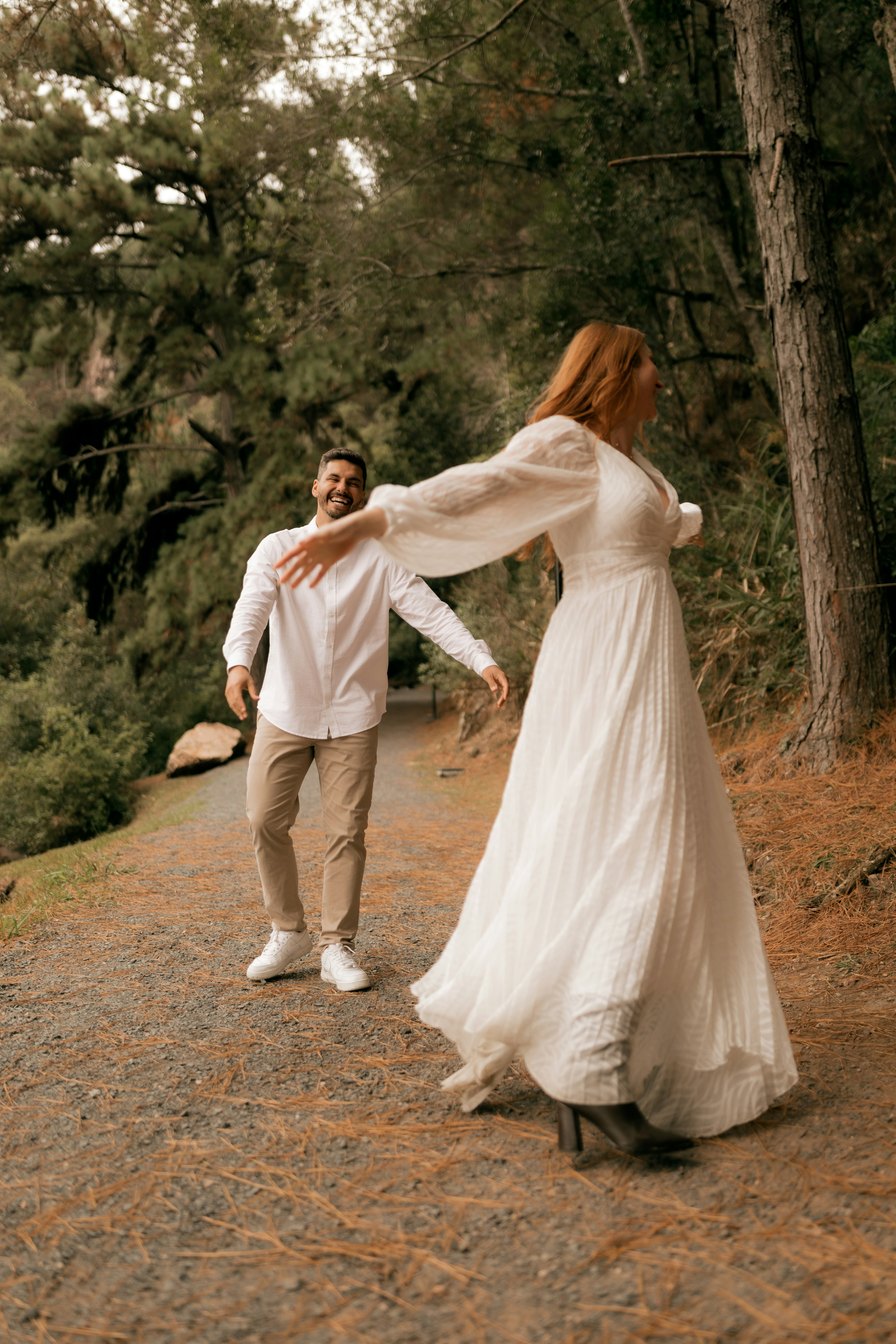 Happy couple dancing outdoors among trees.