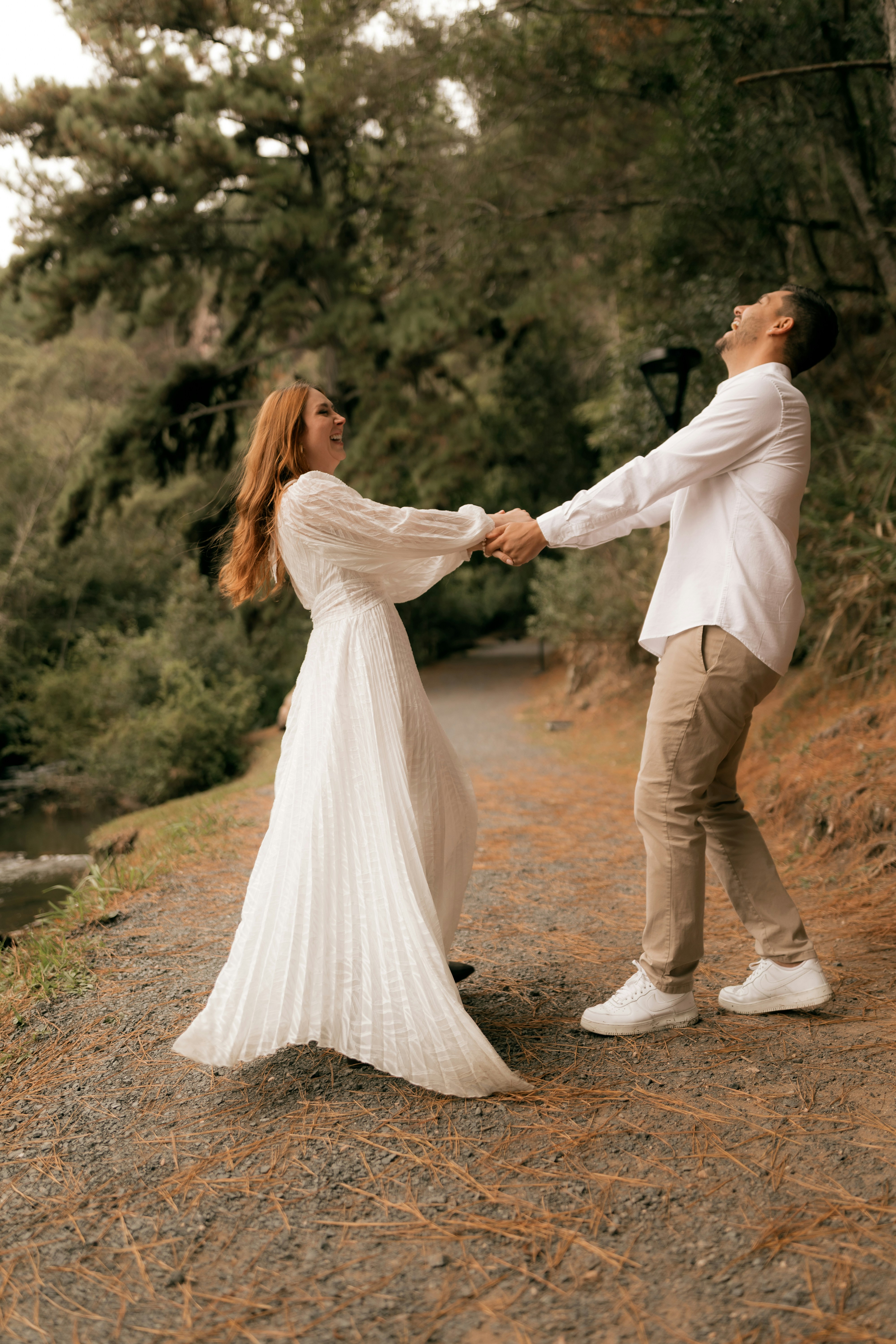 A happy couple spinning and holding hands outdoors.