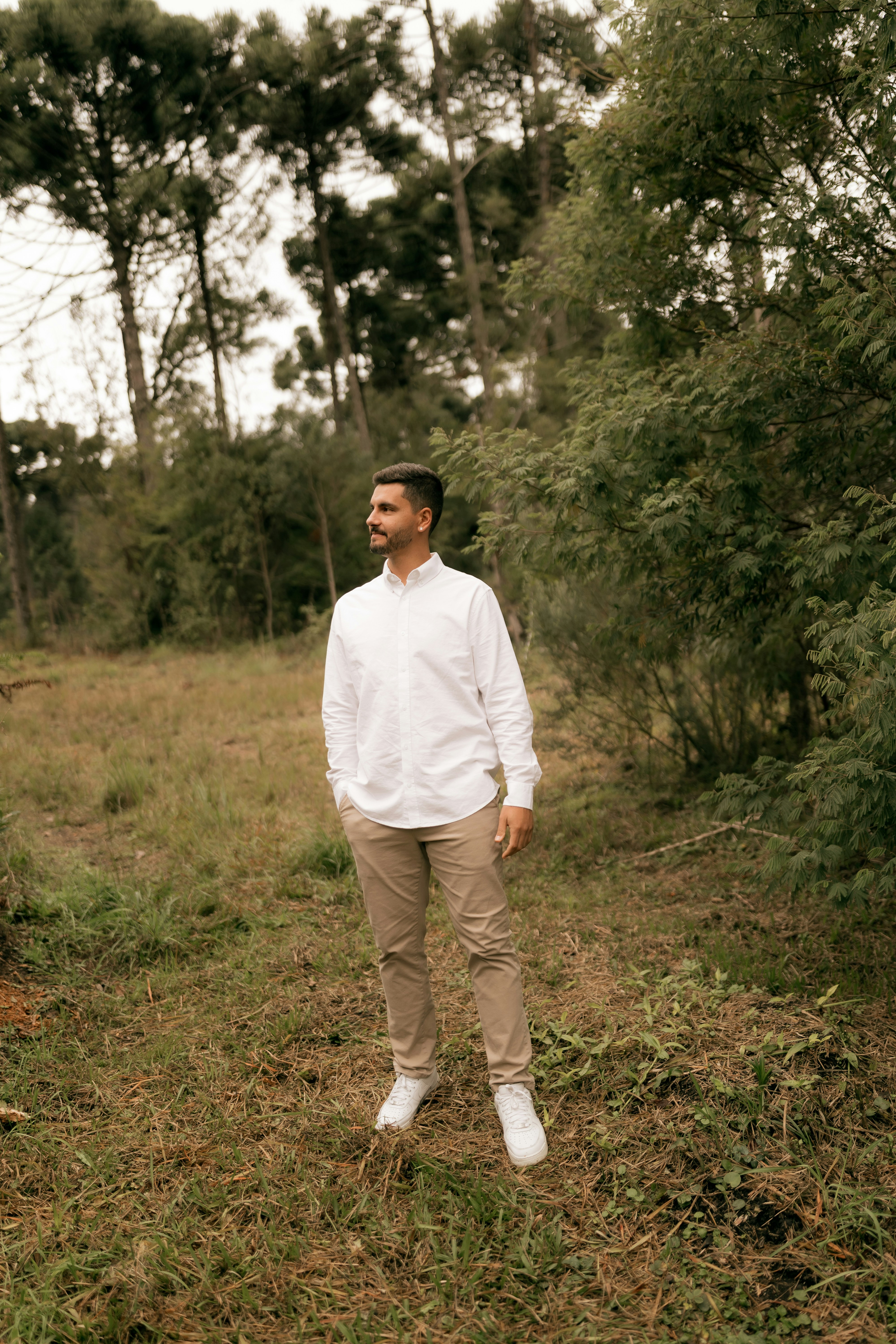 White-shirted wanderer at the edge of a sunlit grove