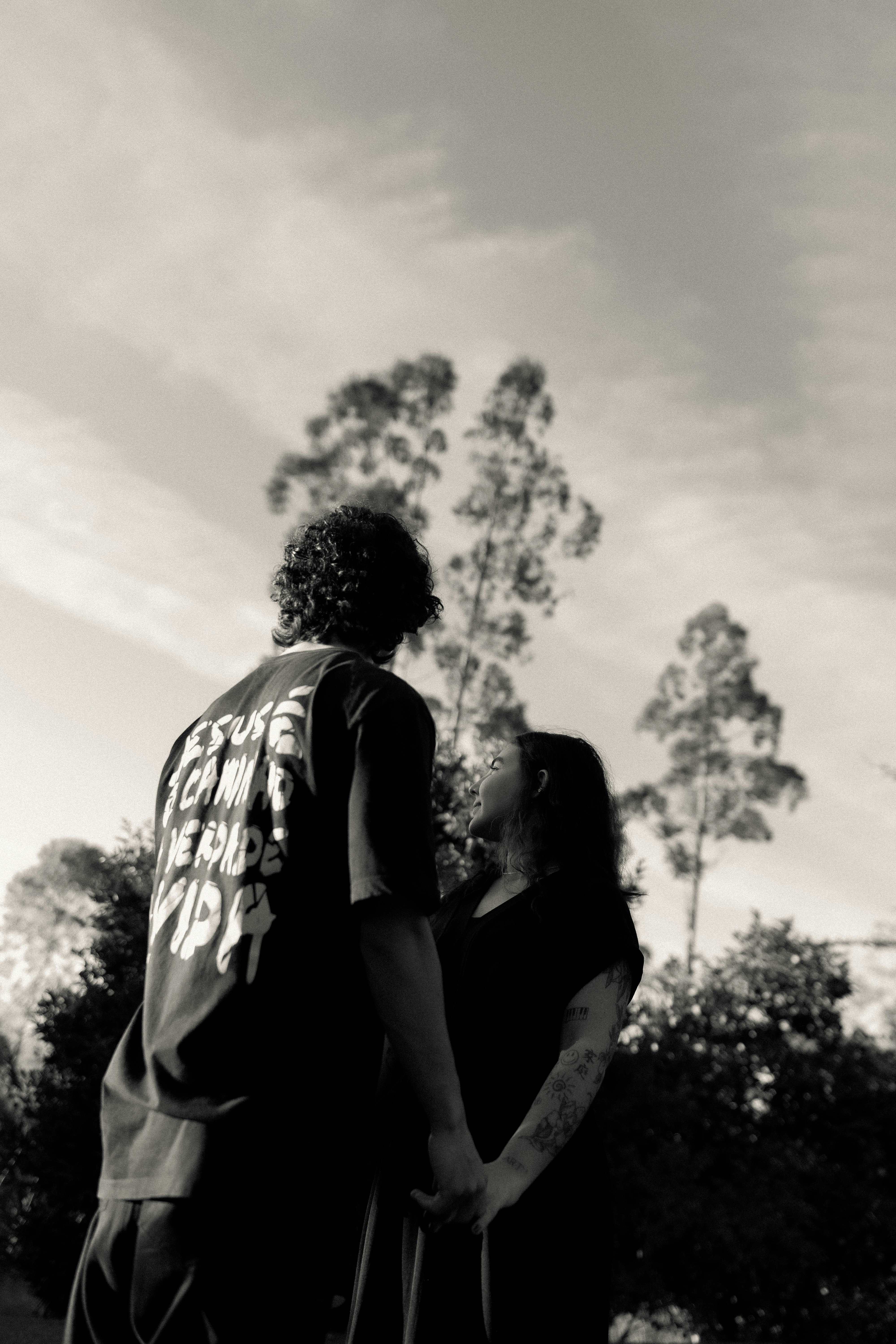 Silhouetted couple holding hands, looking at each other outdoors.