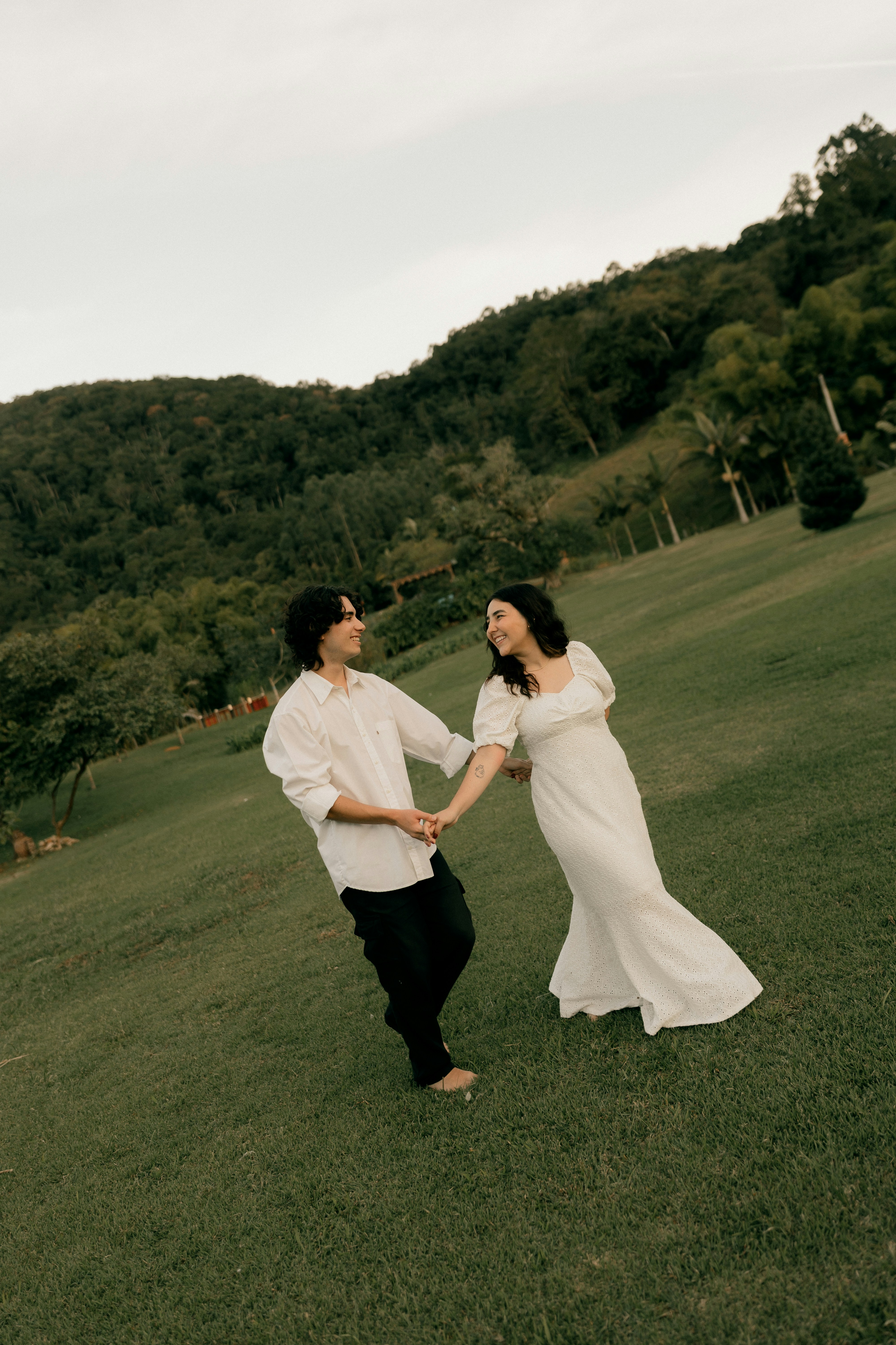 A happy couple dancing in a grassy field.