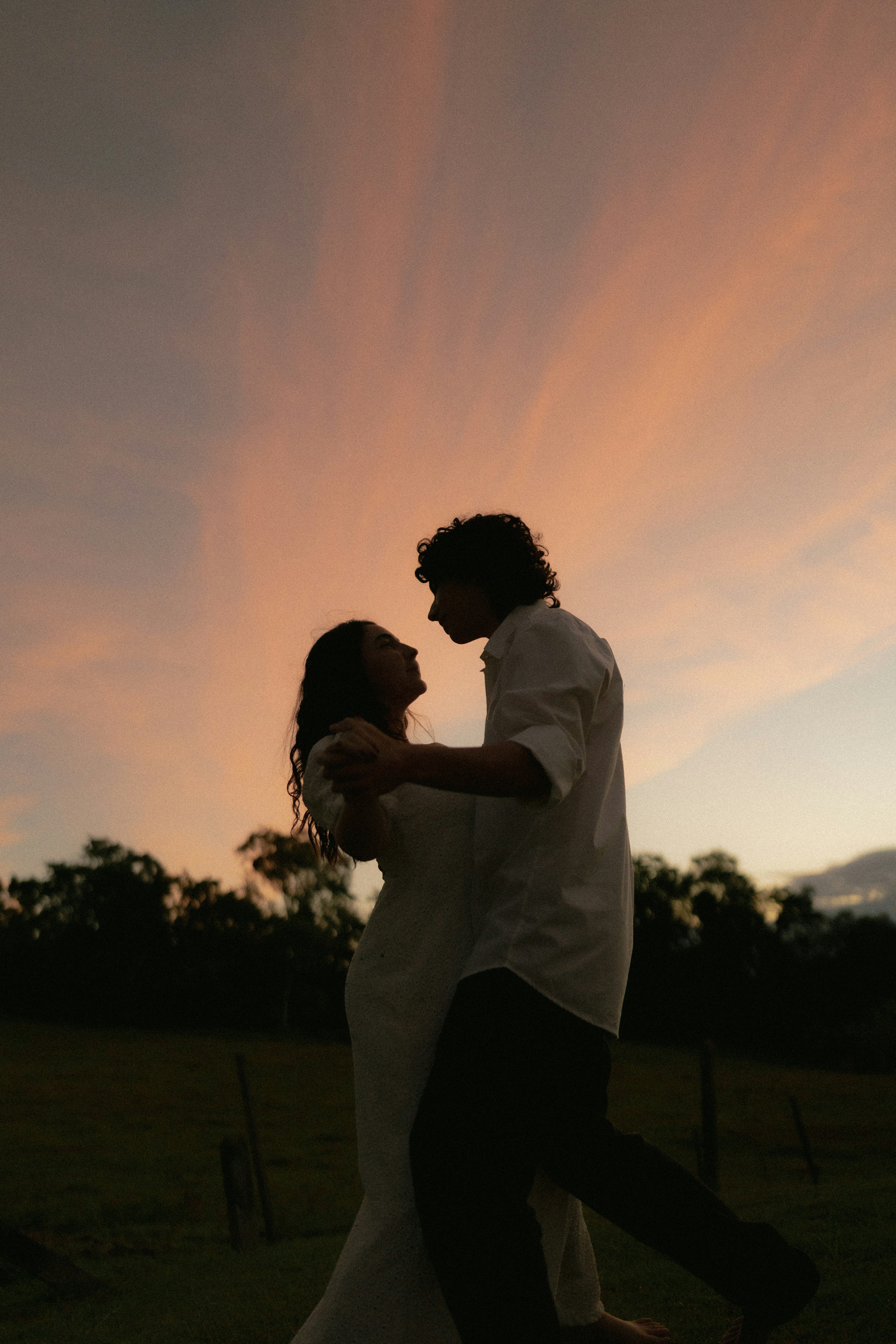 A couple dancing in silhouette against a beautiful sunset sky.