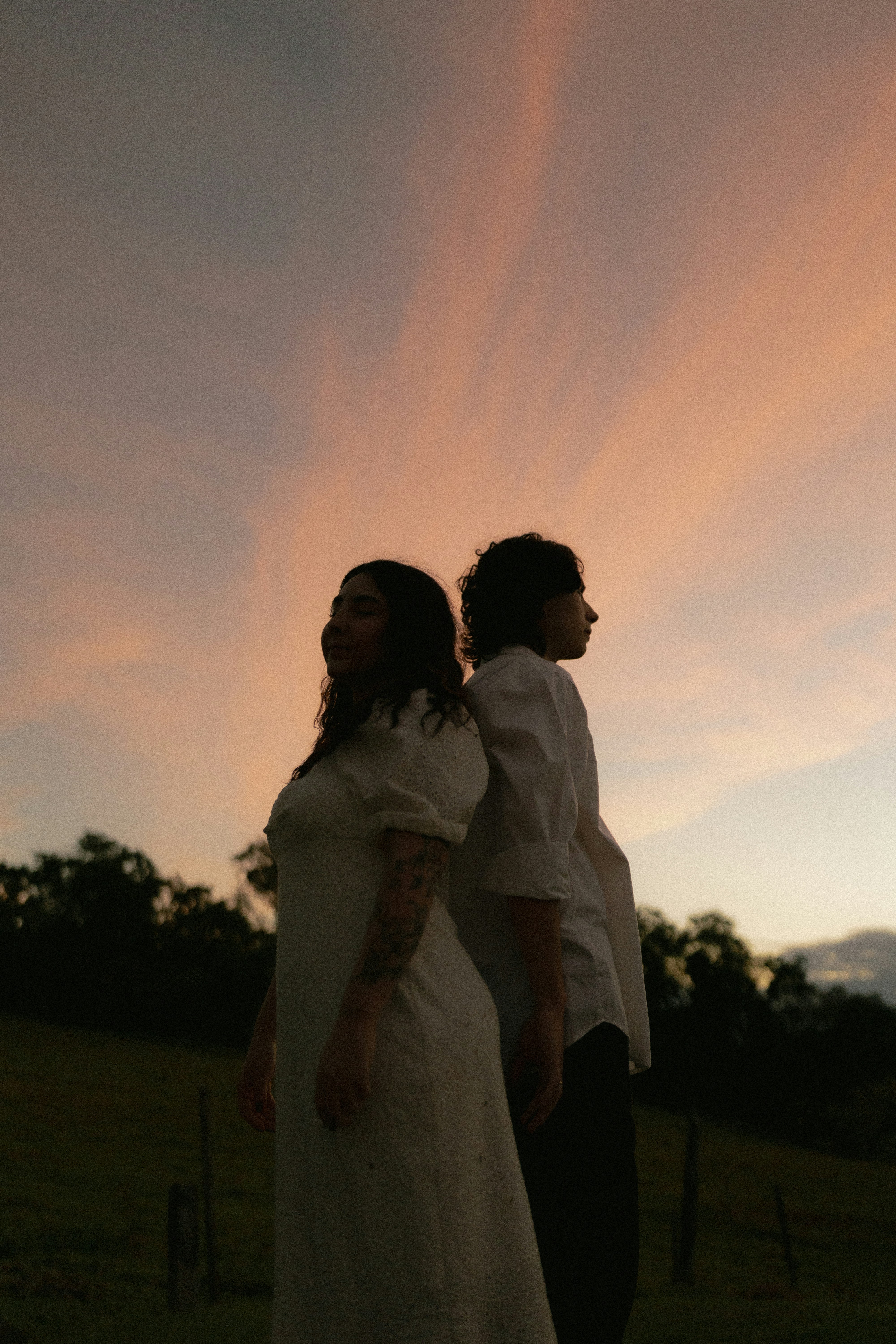 Two silhouettes at dusk: a quiet juxtaposition against an amber sky