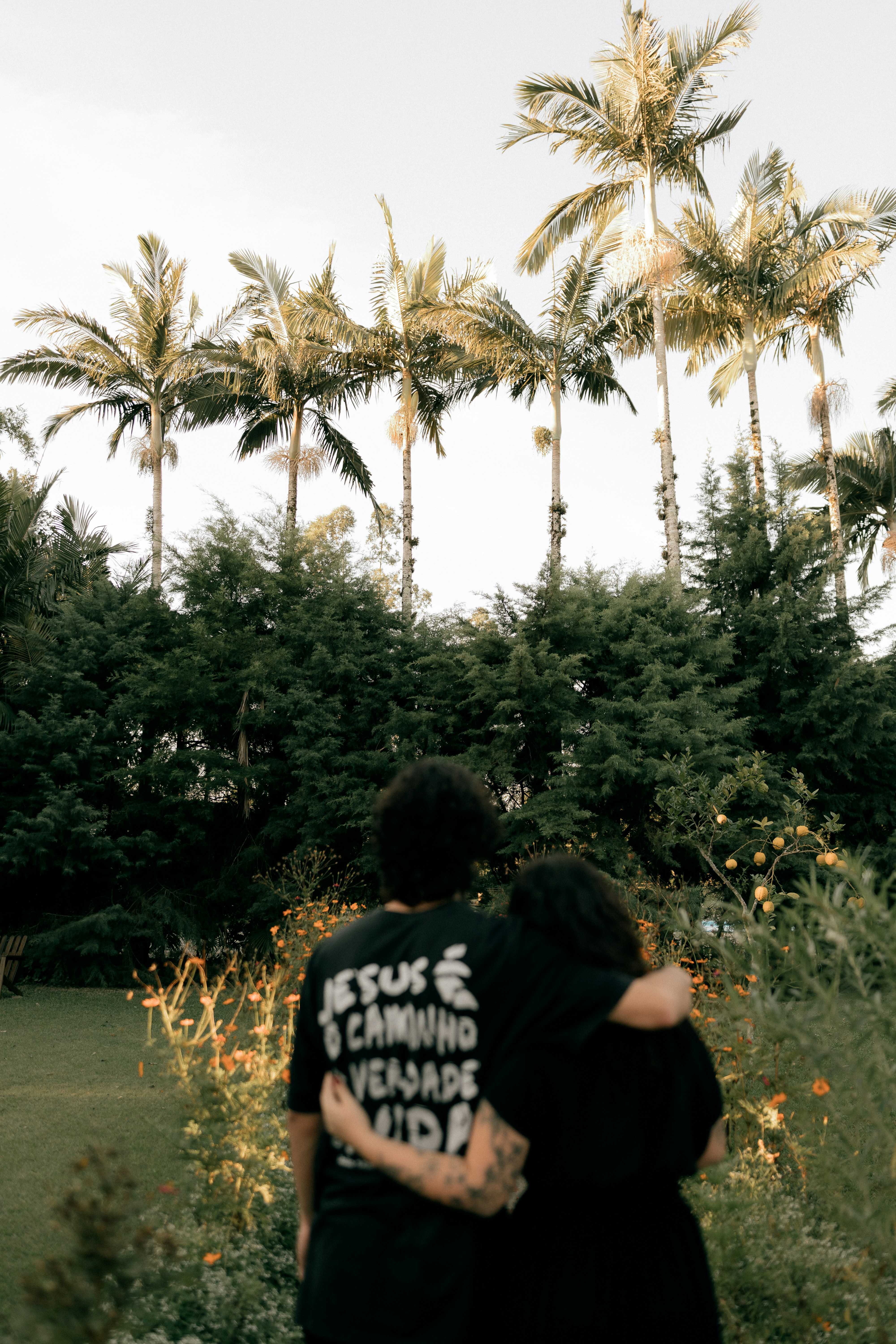 Two in the Garden: Warm Embrace Under Palm Shadows