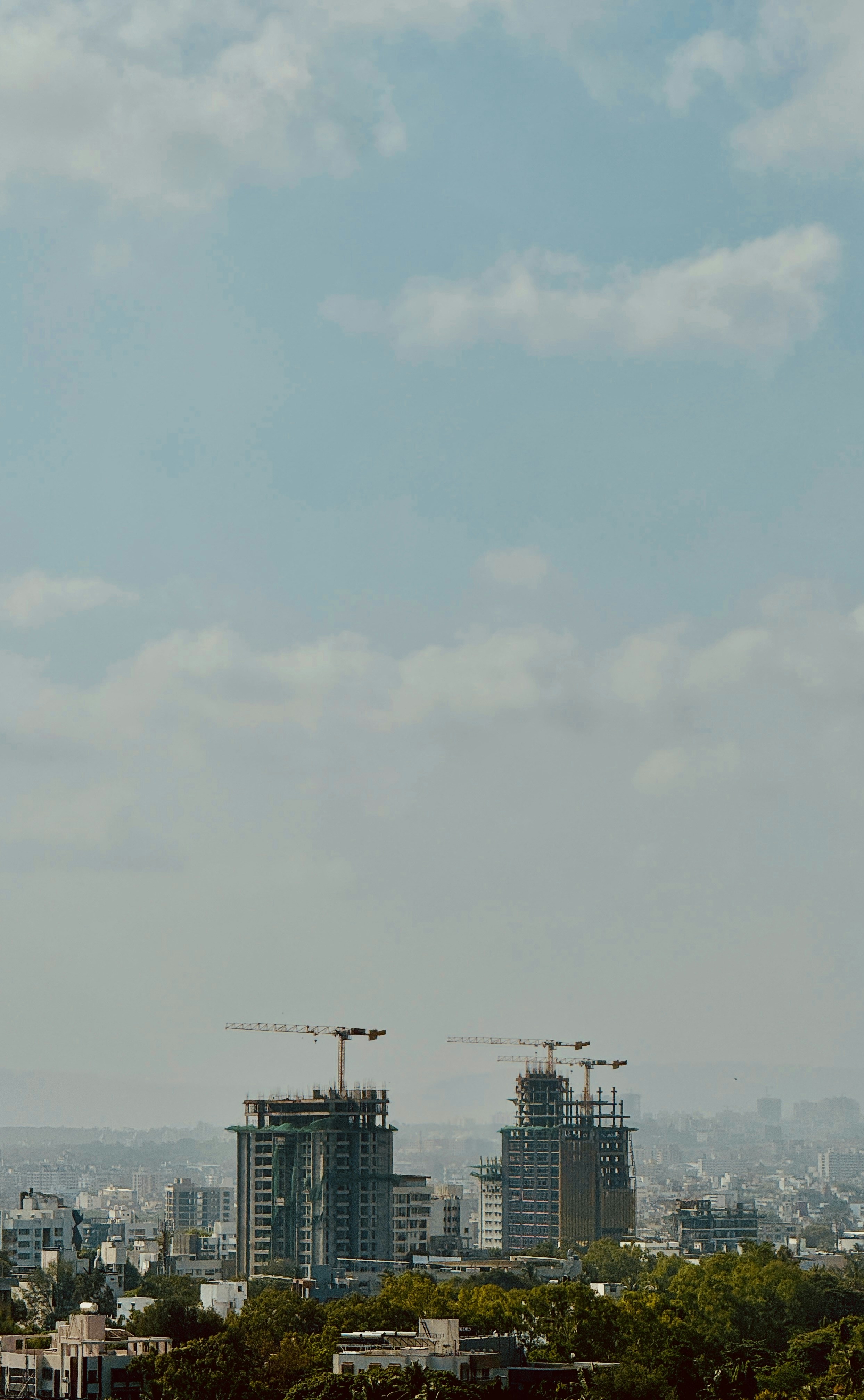 Cityscape Silhouette: Construction Titans Against a Calm Sky