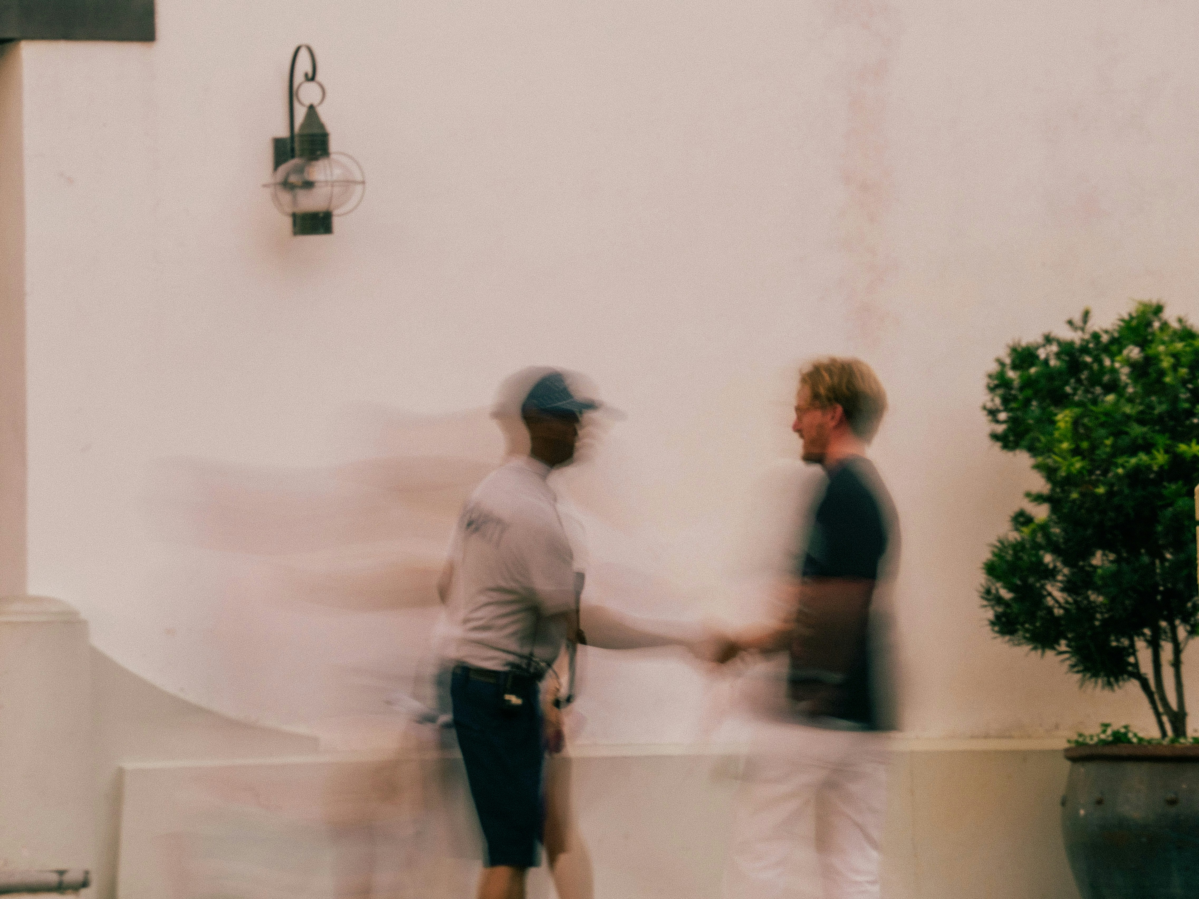 Motion blur and anonymous figures moving through architectural spaces in a modern urban environment.