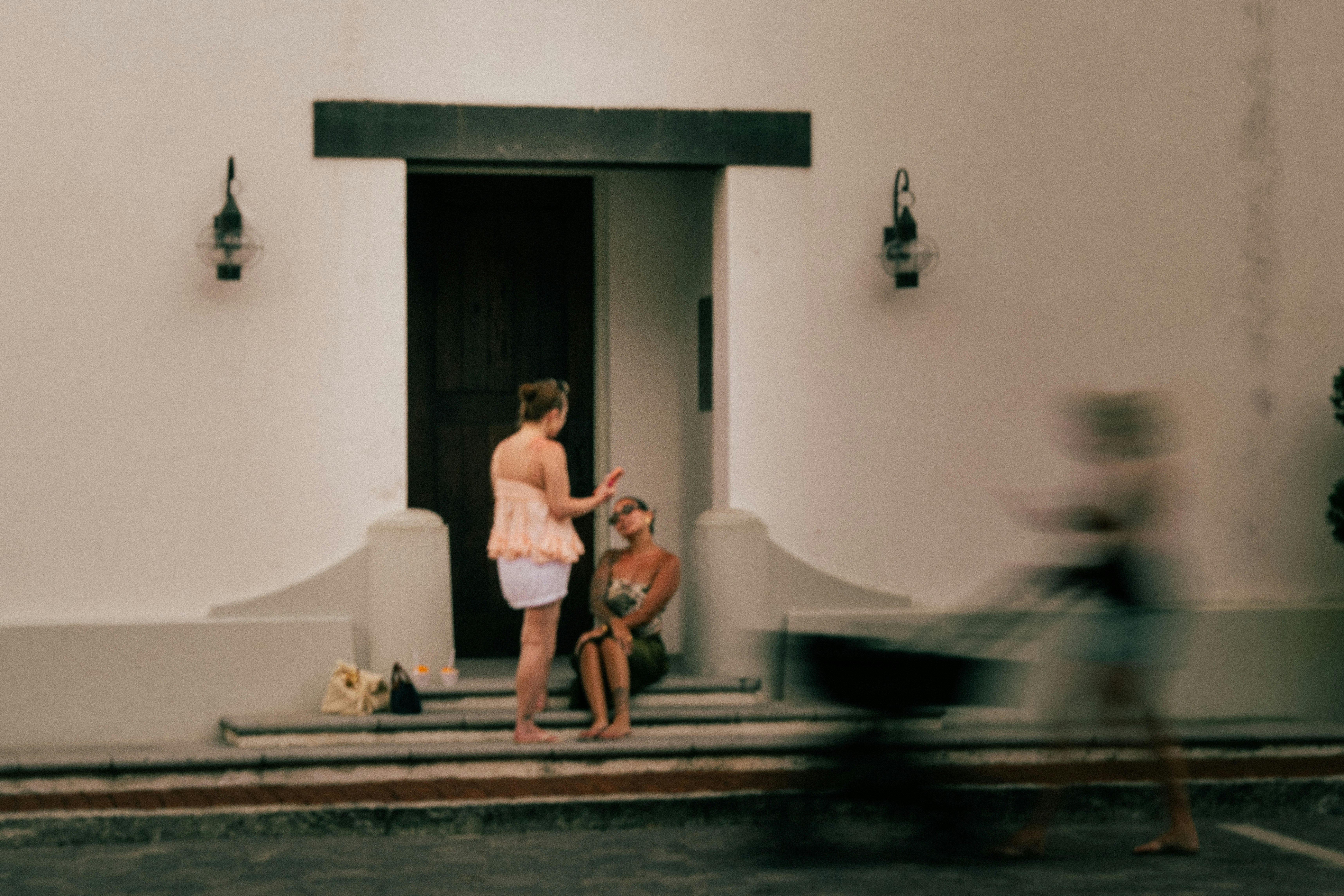 Quiet Moment on a Step: Two figures in warm dusk by a doorway