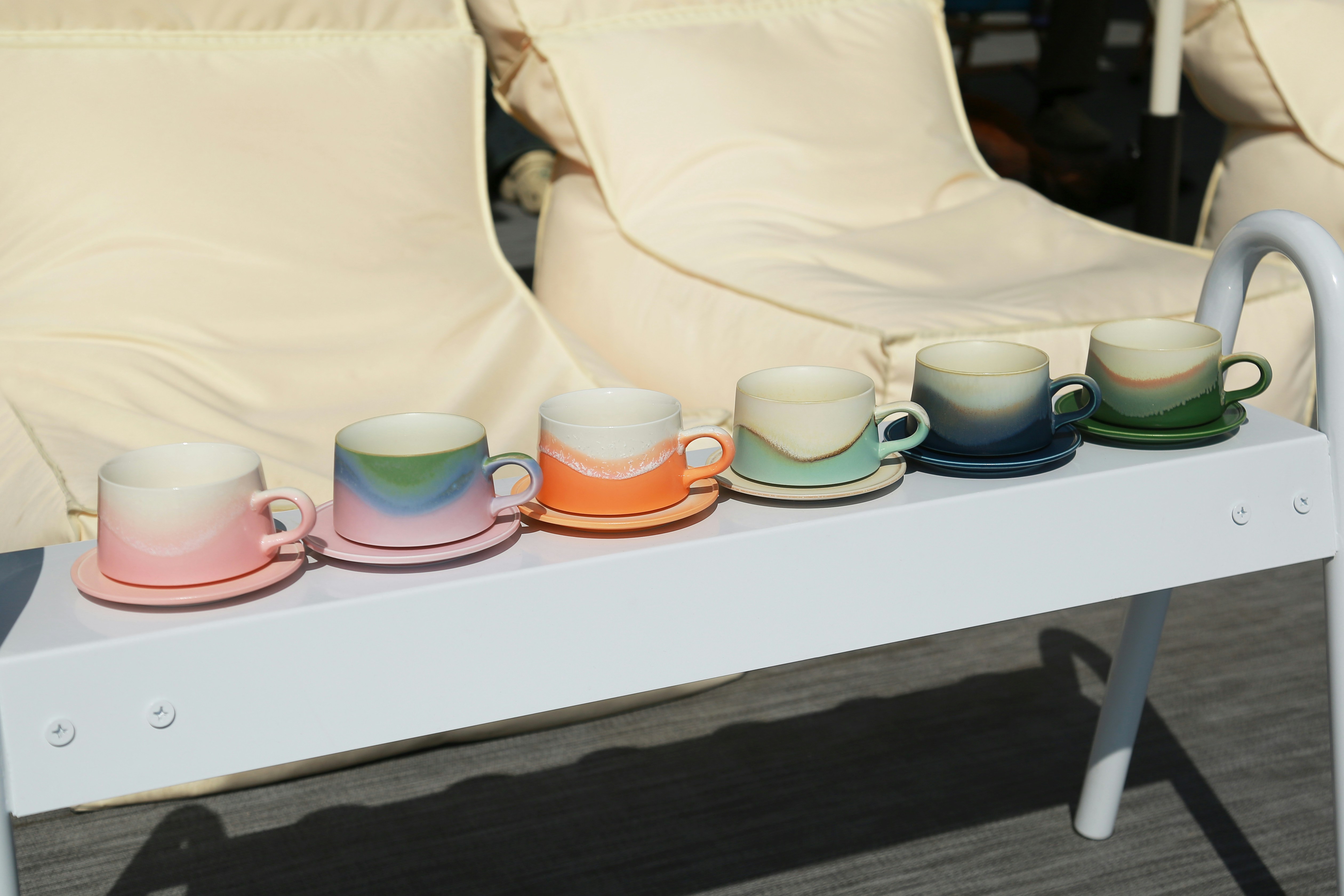 Row of pastel teacups on a sunlit outdoor table