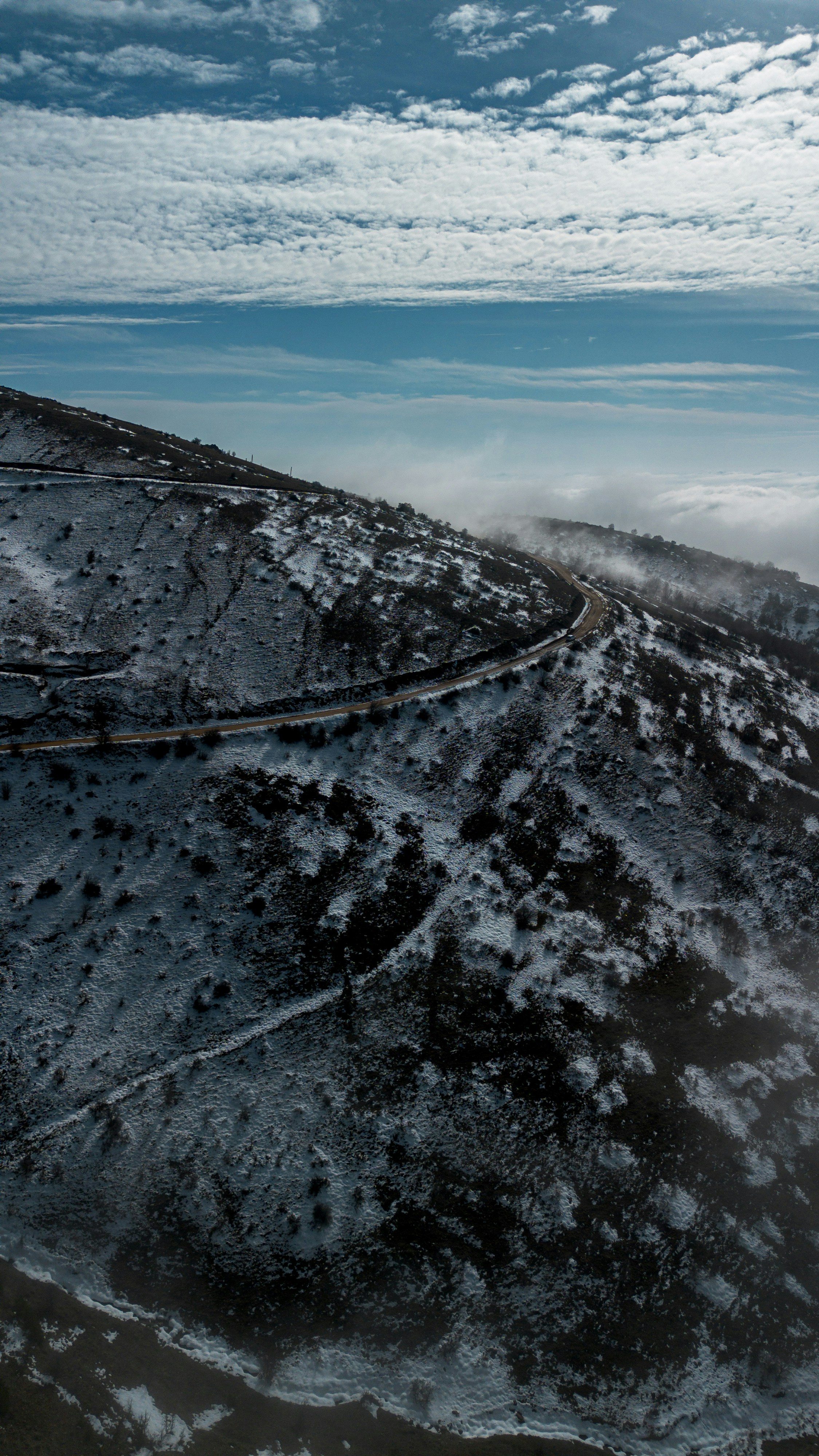 Snow-Capped Switchback: A Winding Road Carves Through a Misty Ridge