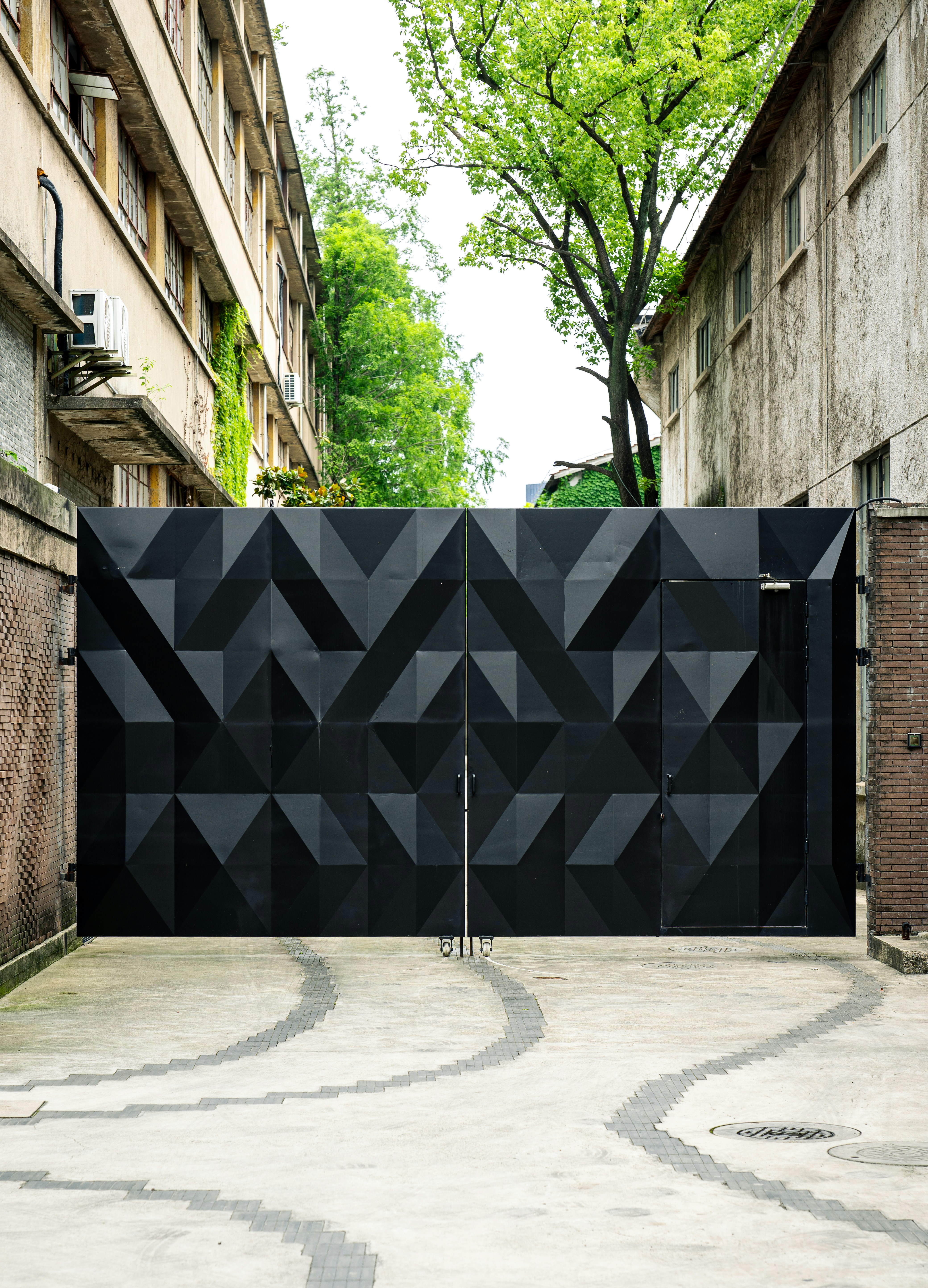Geometric Gate: A Modern Monolith Framed by Quiet Urban Trees