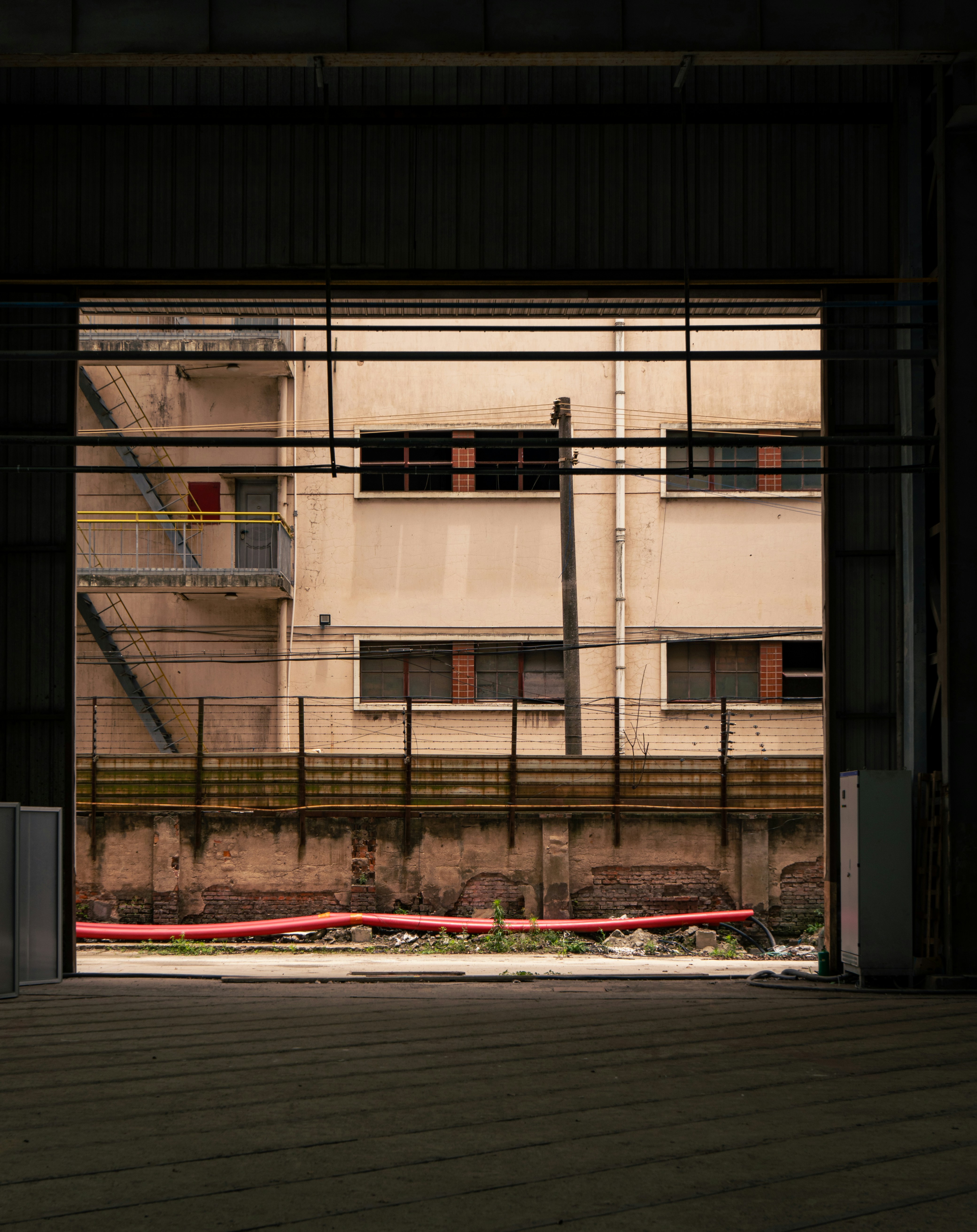 Edge of the Factory Gate: Distant Building Through a Dim Frame