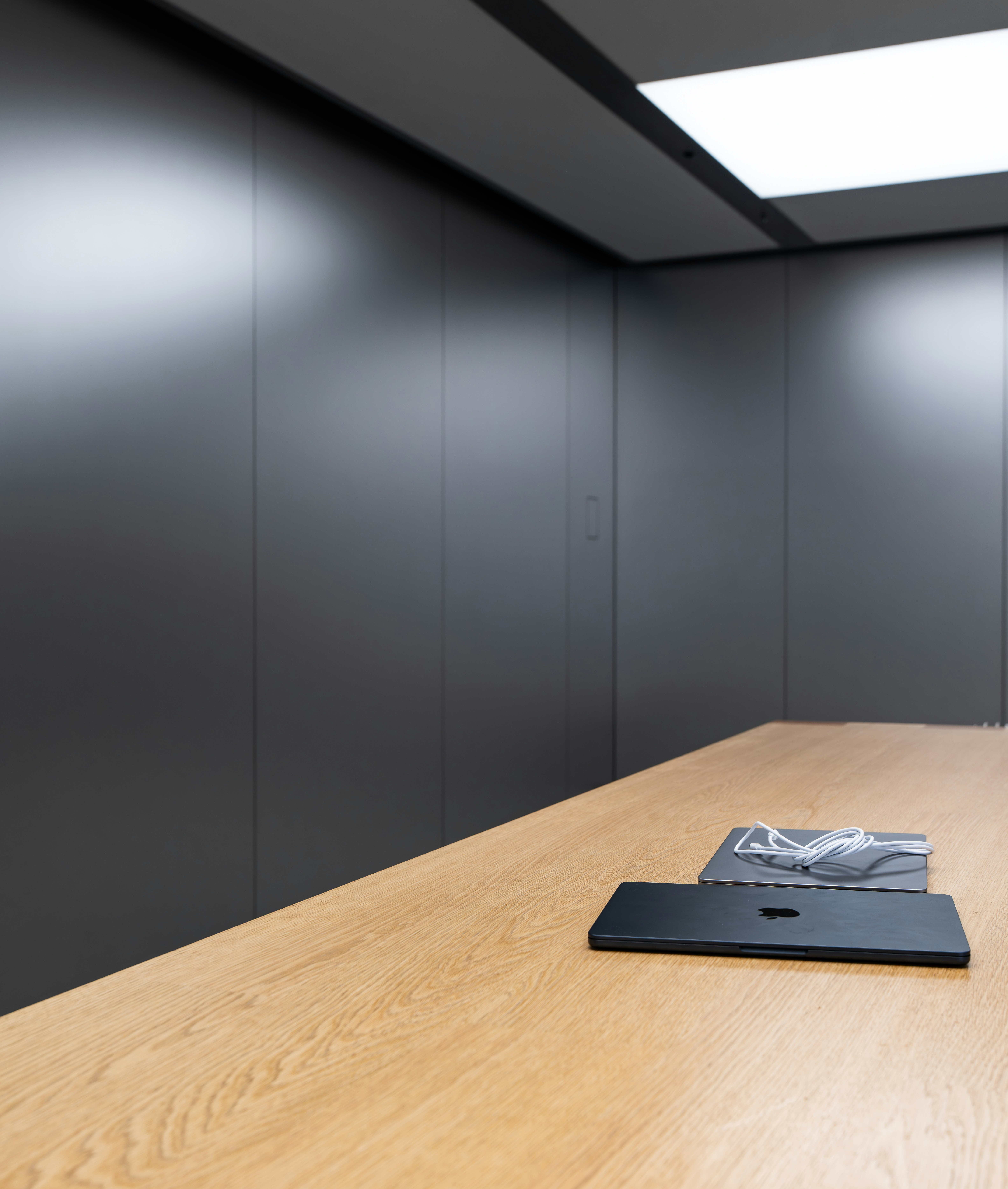 Empty Boardroom, Quiet Technology: A Laptop and Notebook Rest on a Sunlit Wood Table
