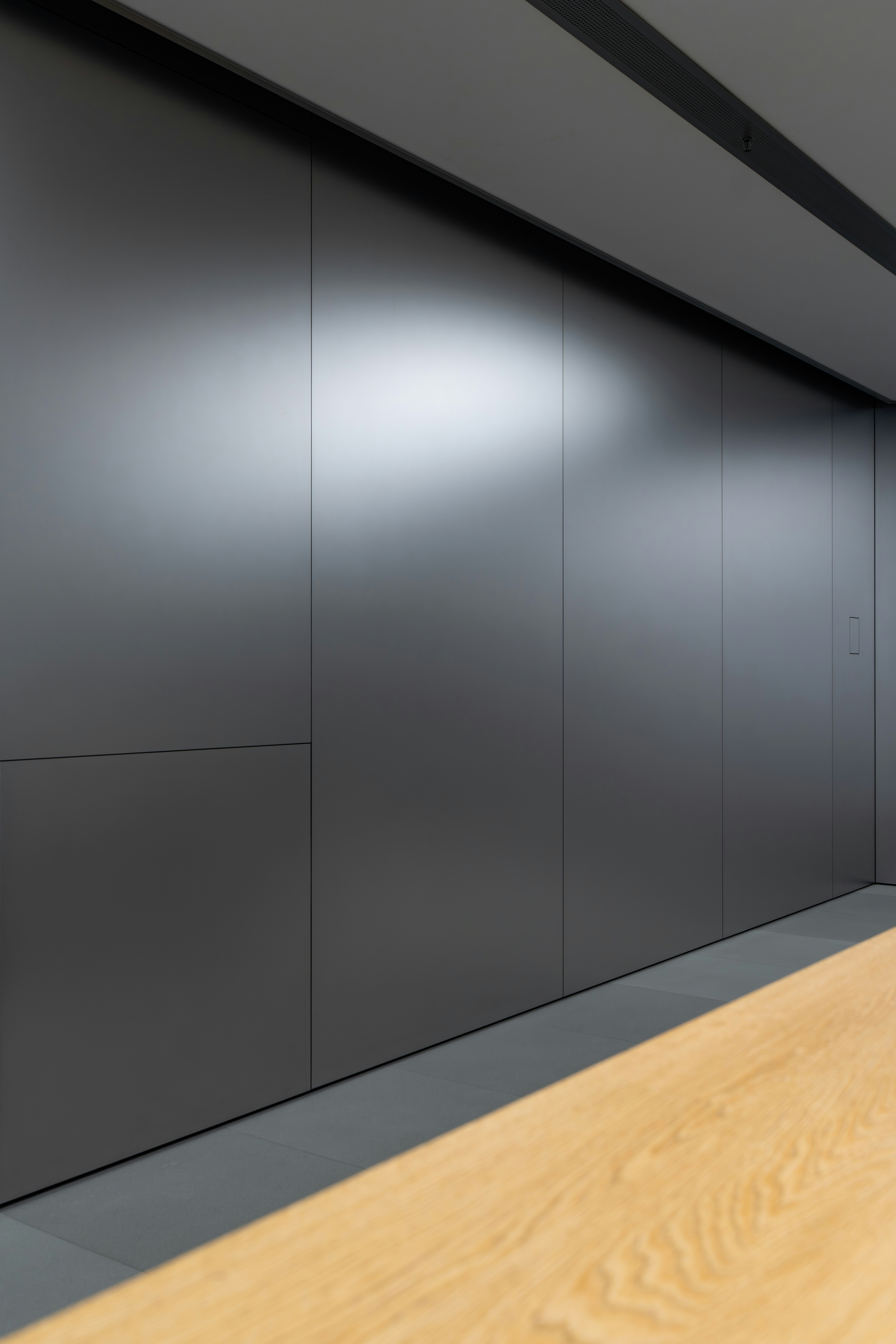 A sleek dark gray wall with a light wooden surface.