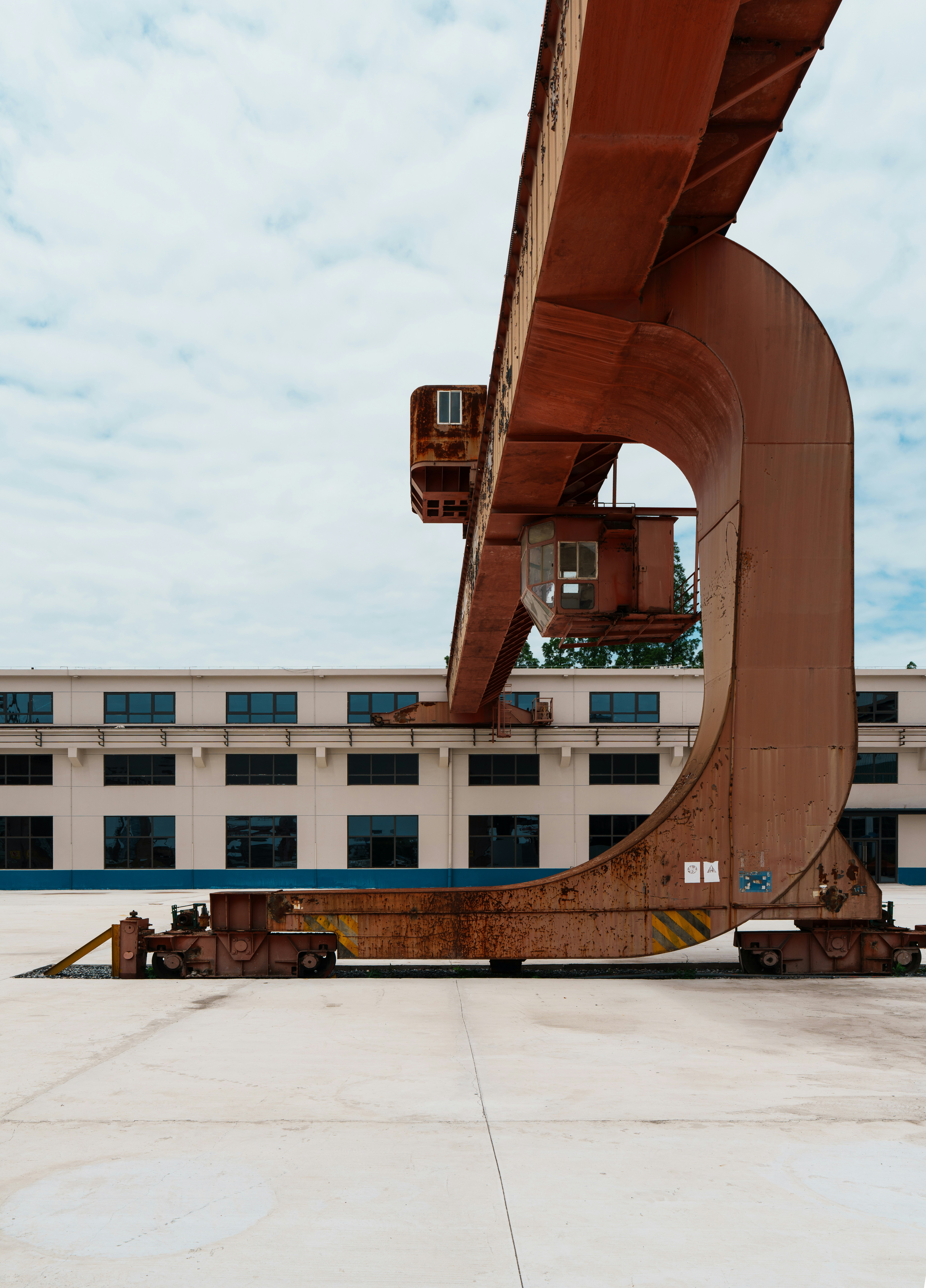 Industrial Arc: A Rusty Crane Frame Framing a Modern Warehouse