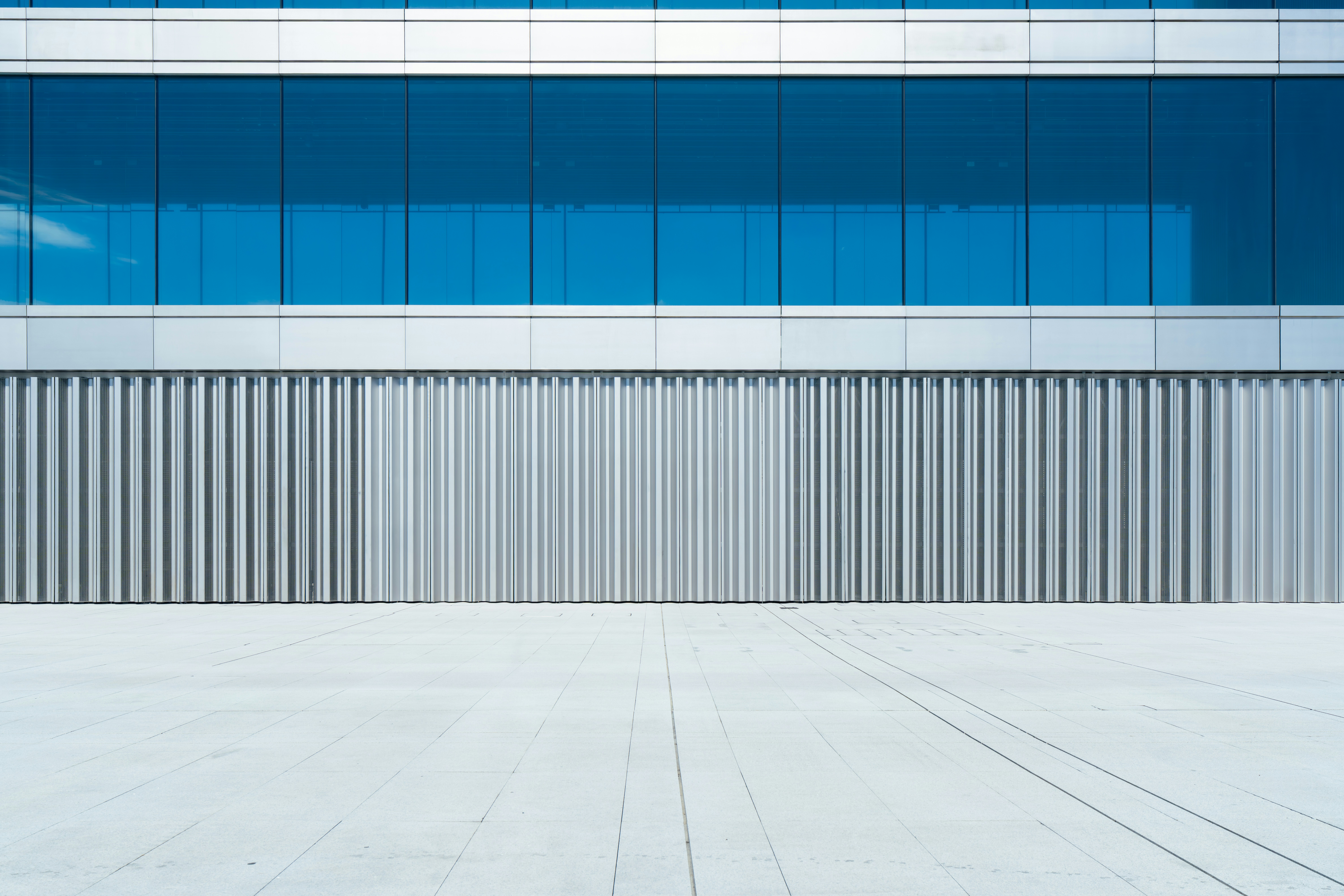 Modern building facade with blue windows and grey textured wall.