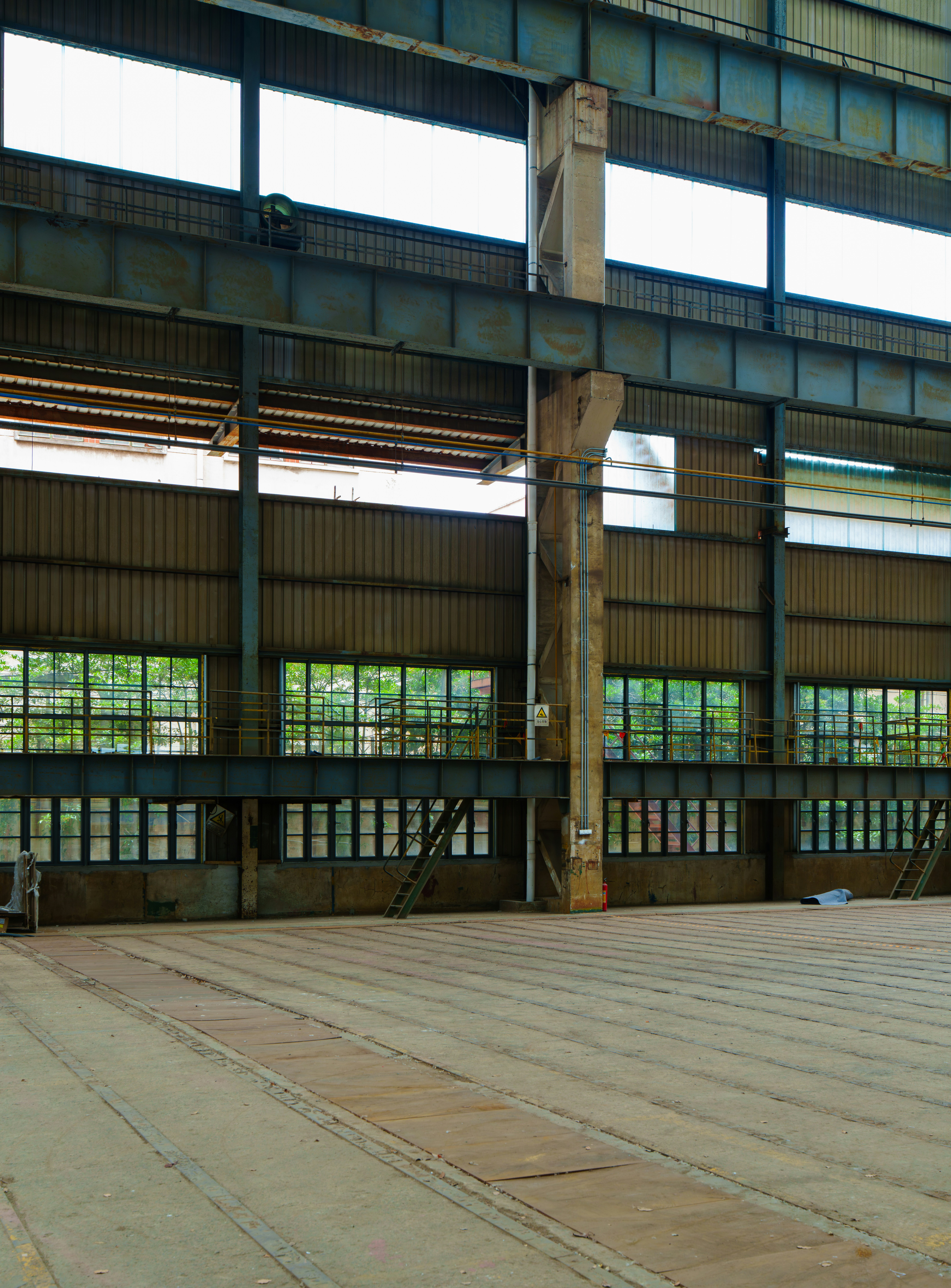 Large empty industrial warehouse interior with metal beams and windows.