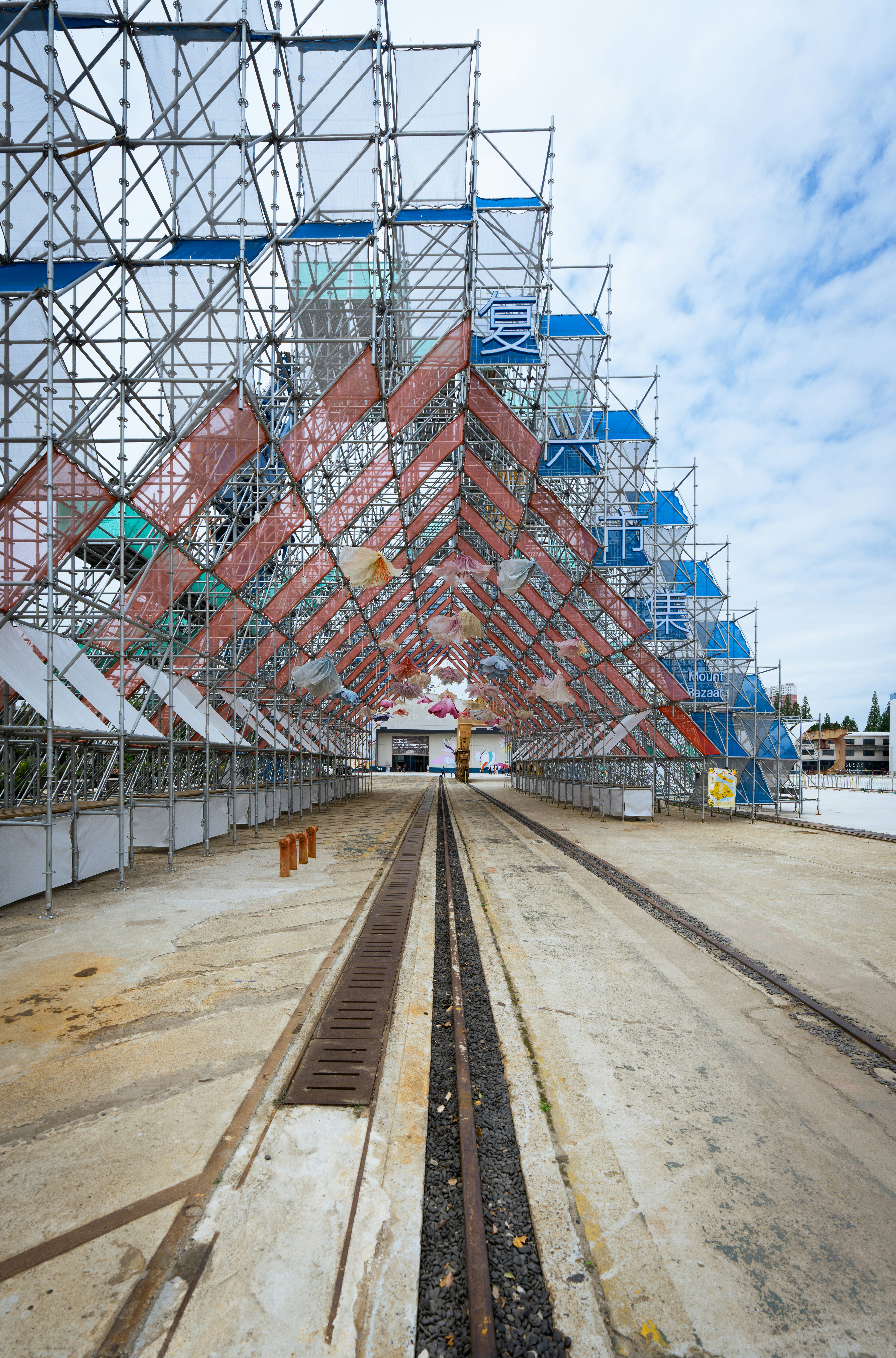 Massive scaffolding structure spanning over old train tracks.