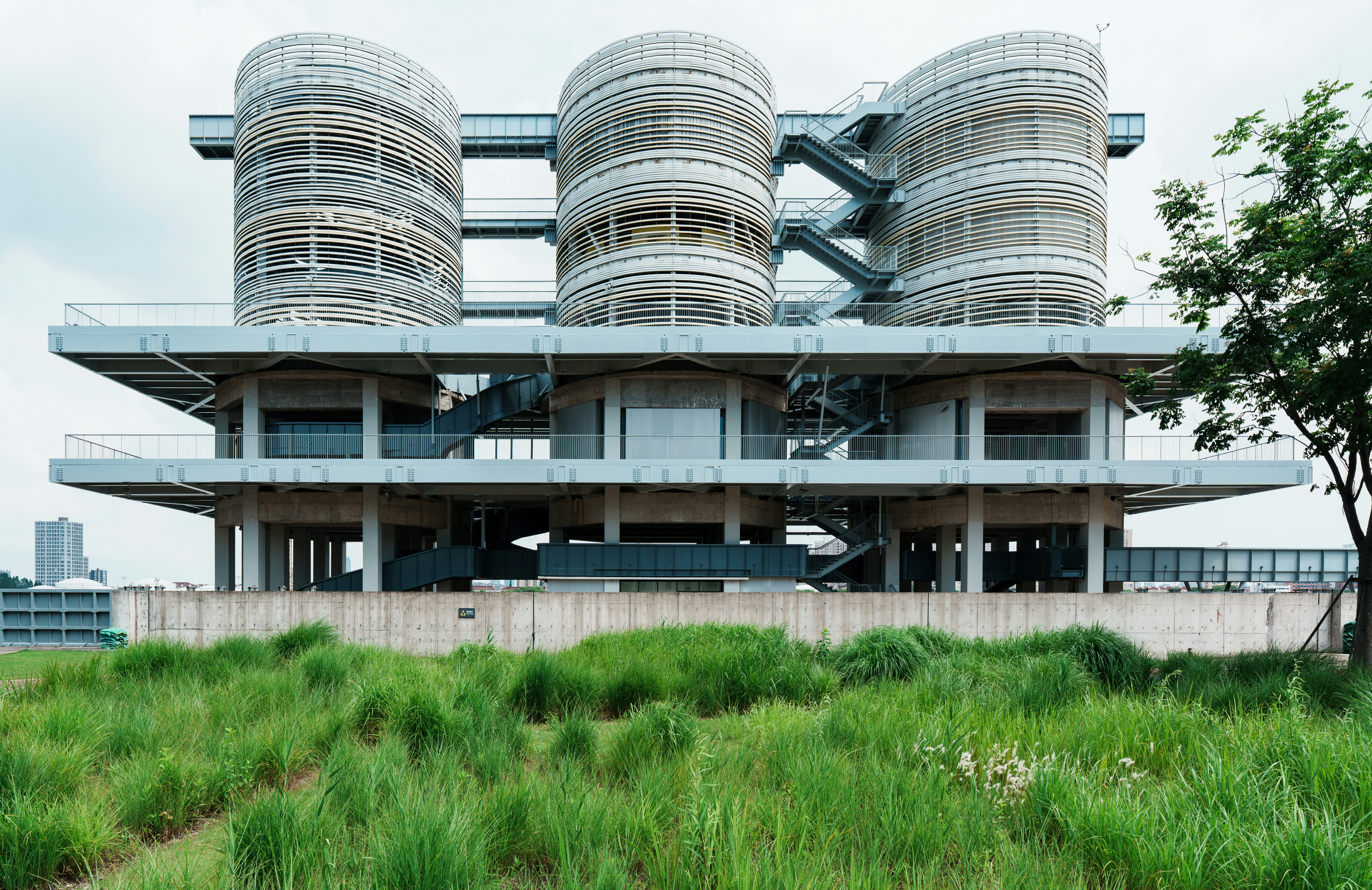 Modern building with three cylindrical towers above green grass.