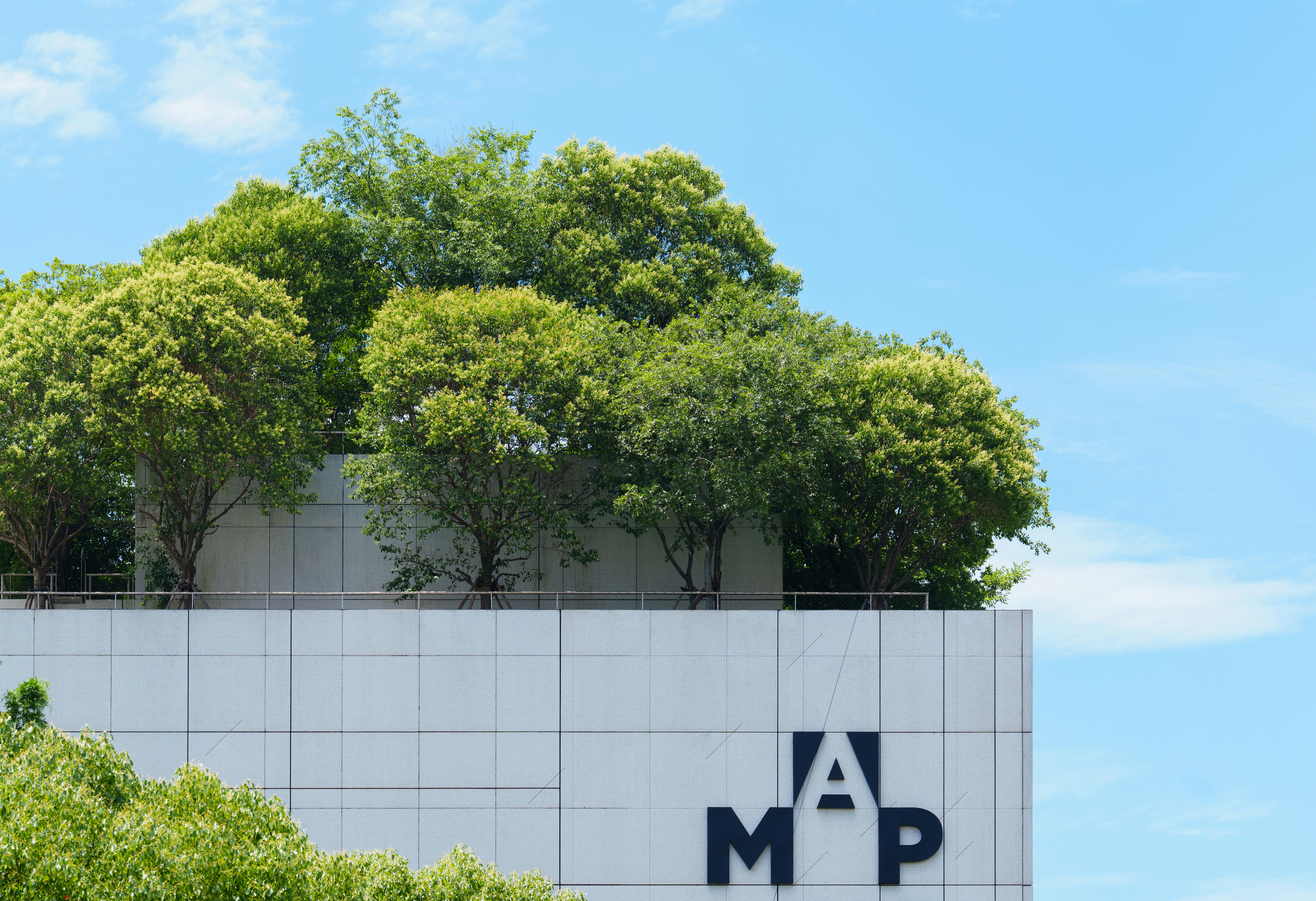 Modern building with a lush rooftop garden under blue sky.