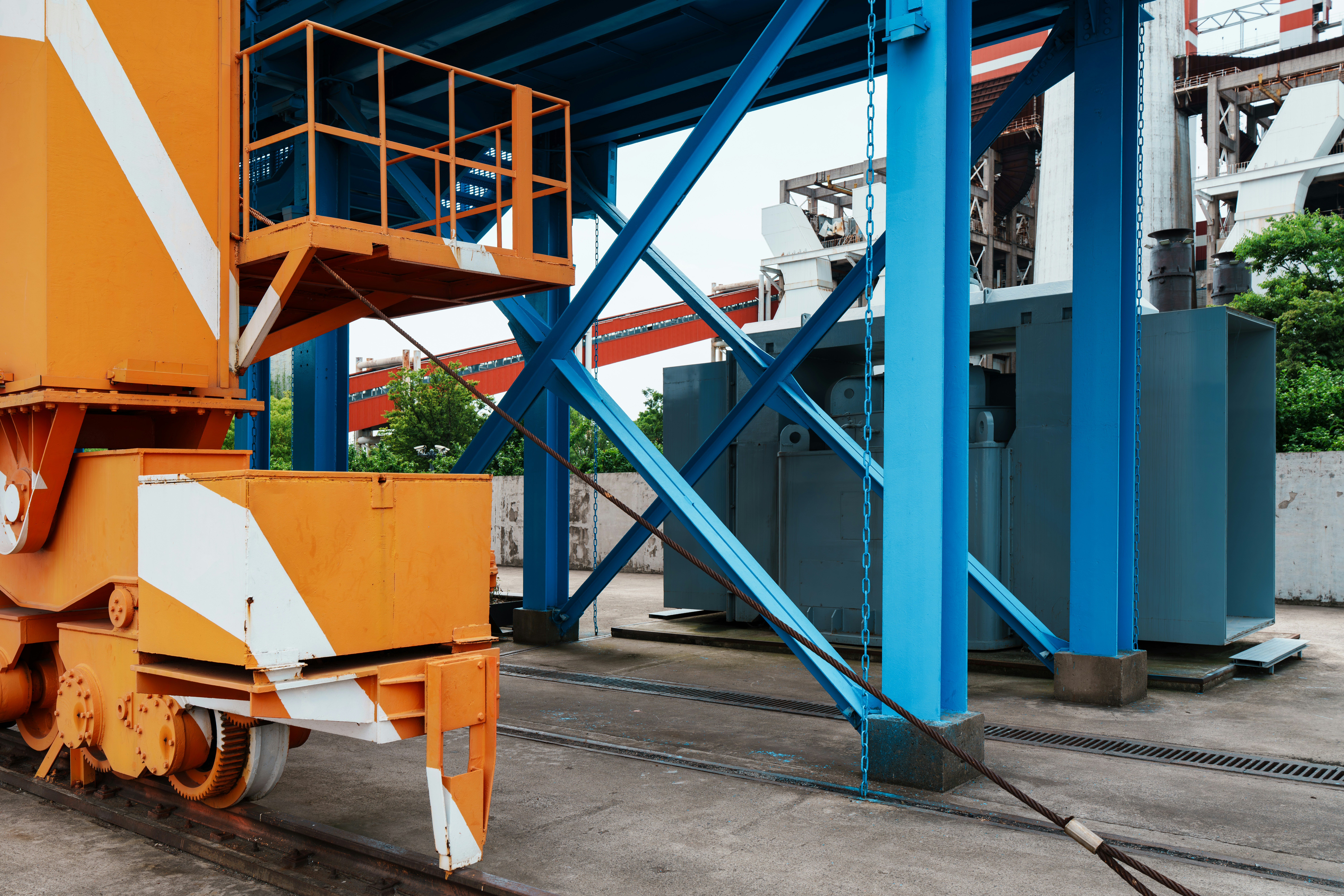 Large orange industrial crane base and blue structural supports.