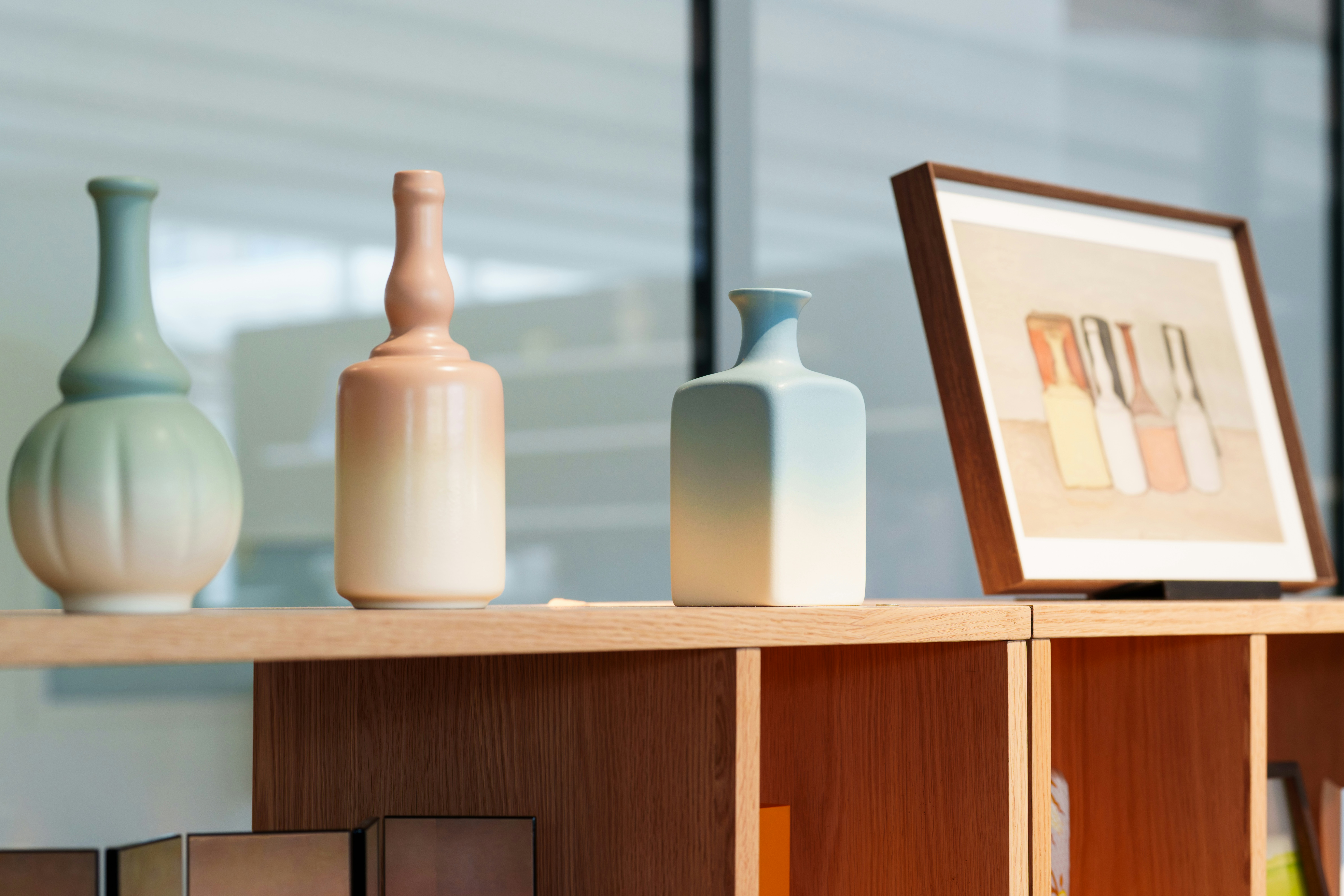 Decorative vases and framed art on a light wooden shelf.