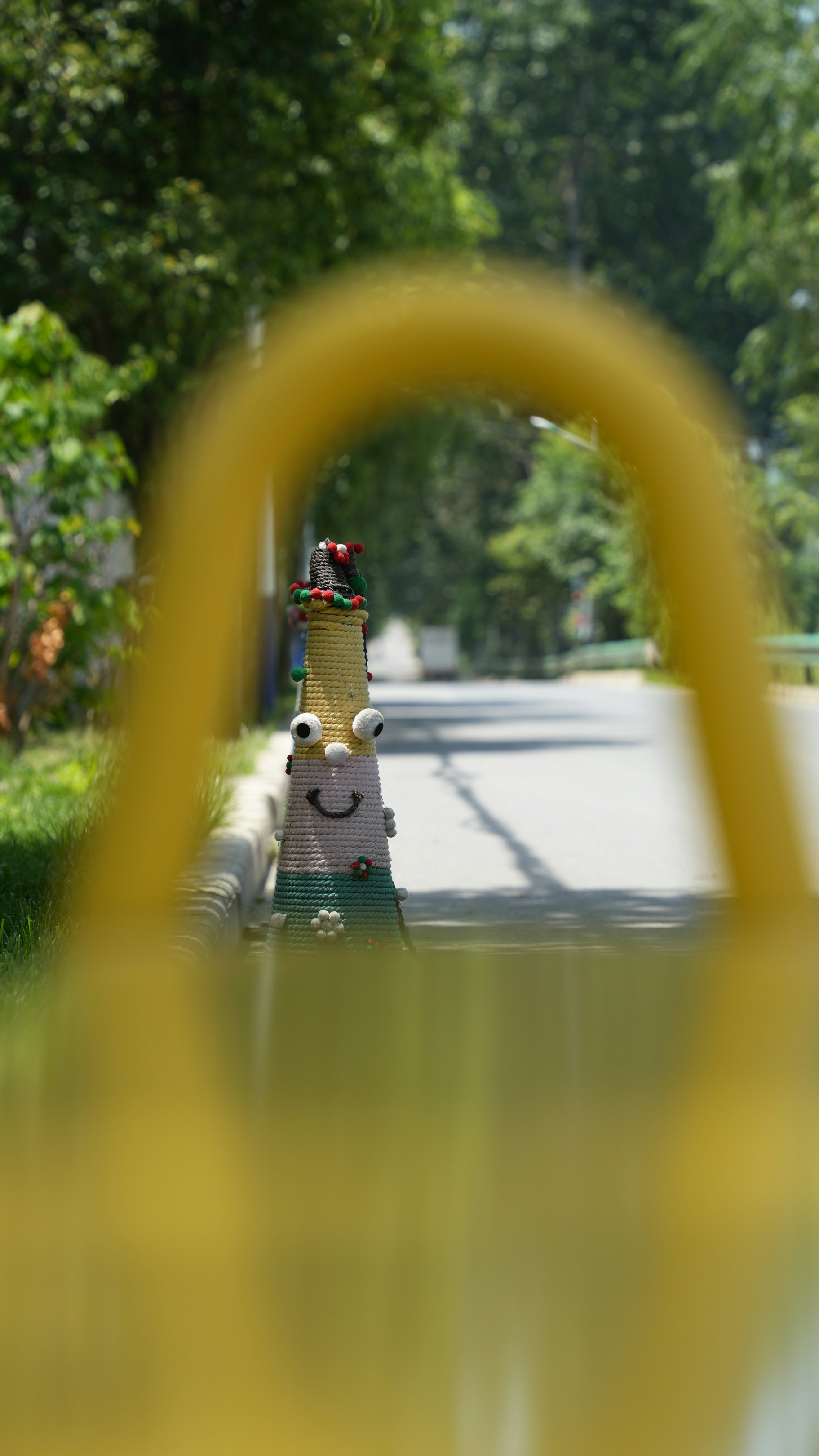 Smiling knit creature on a sunny street framed by a curved yellow frame