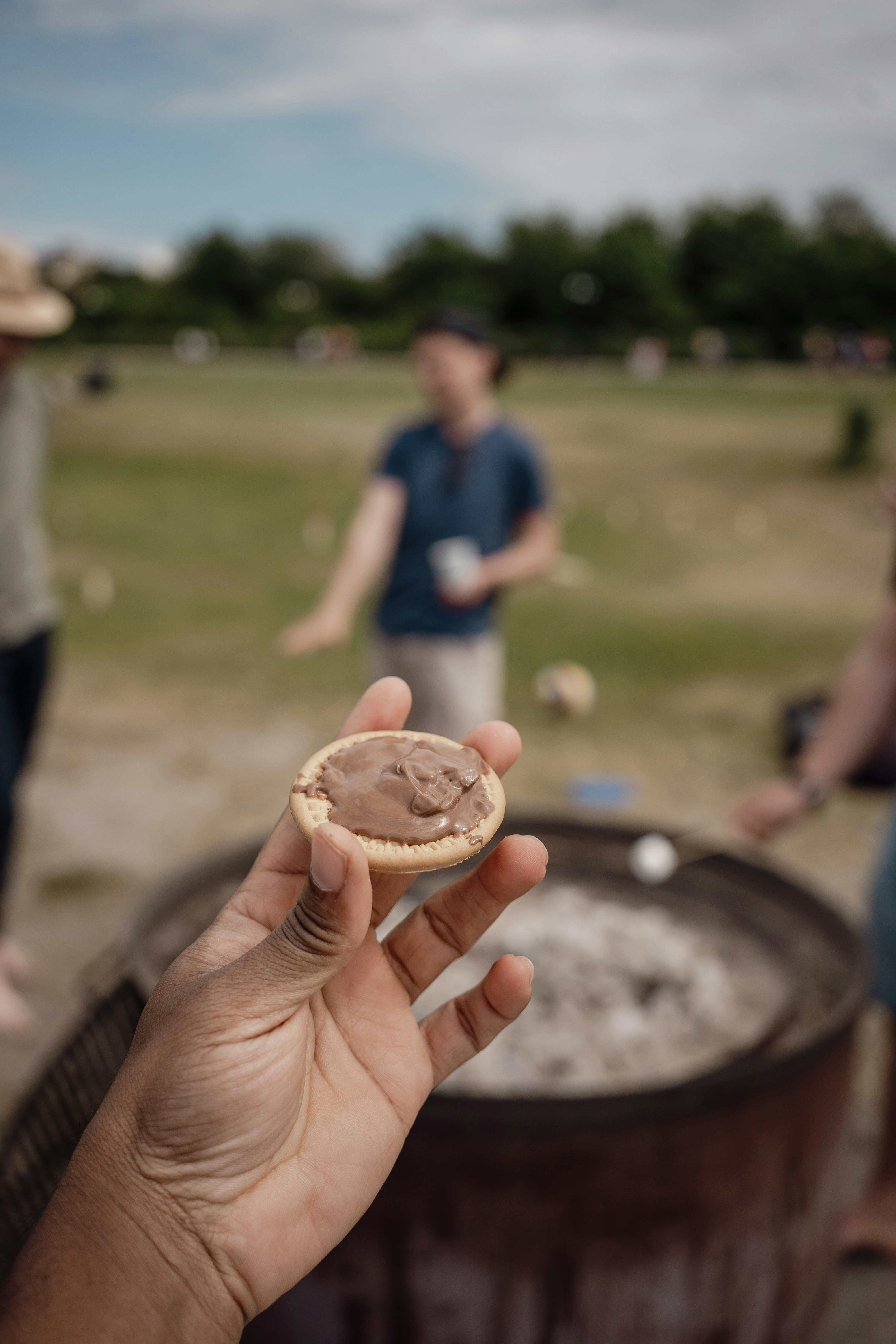 Handheld Treat: Nutella Tart Centered Against a Social Outdoor Scene