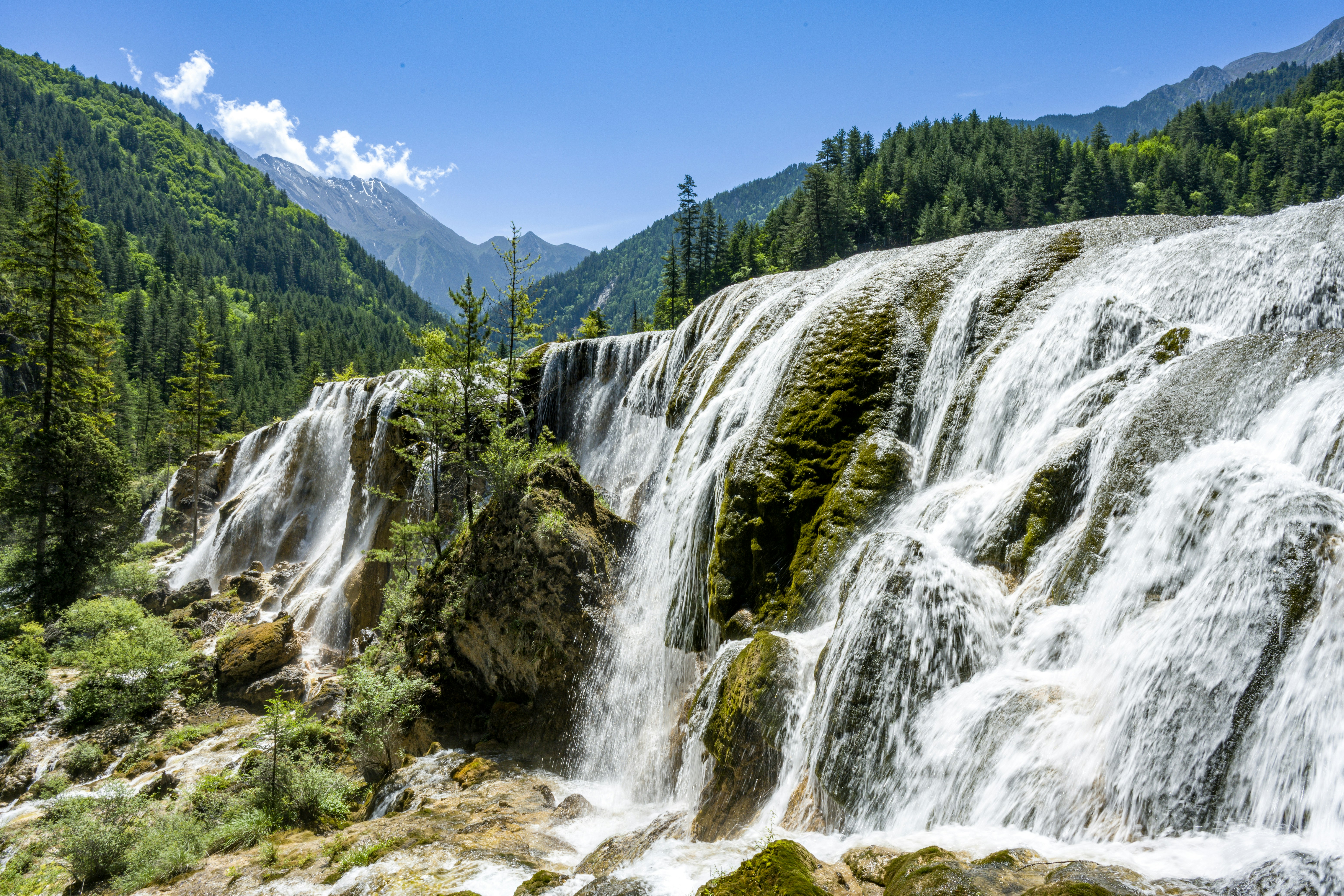 Majestic waterfall cascades down a mossy mountain slope.