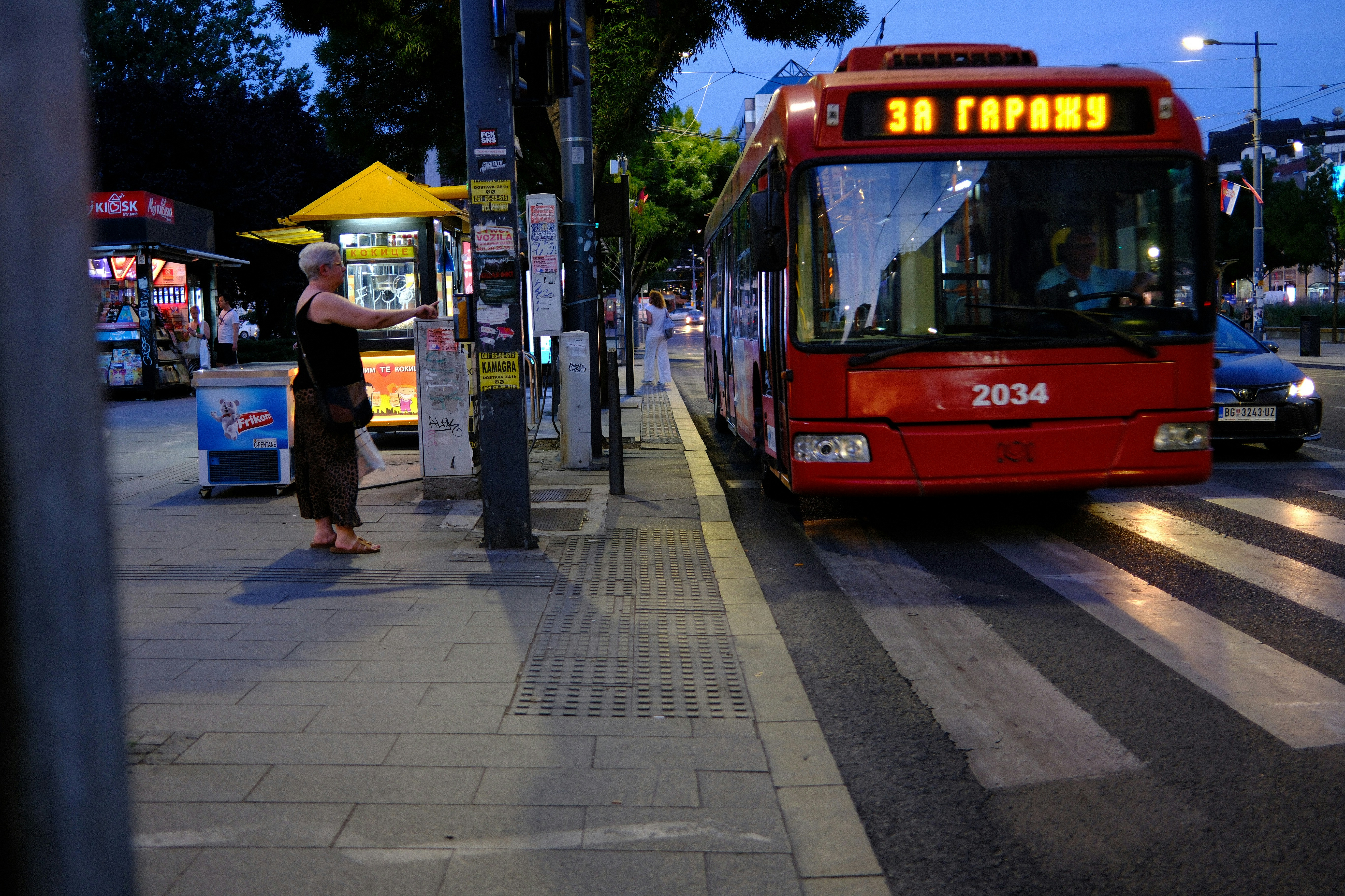 Late-Evening Transit: A Red Bus Docks at a Quiet City Stop