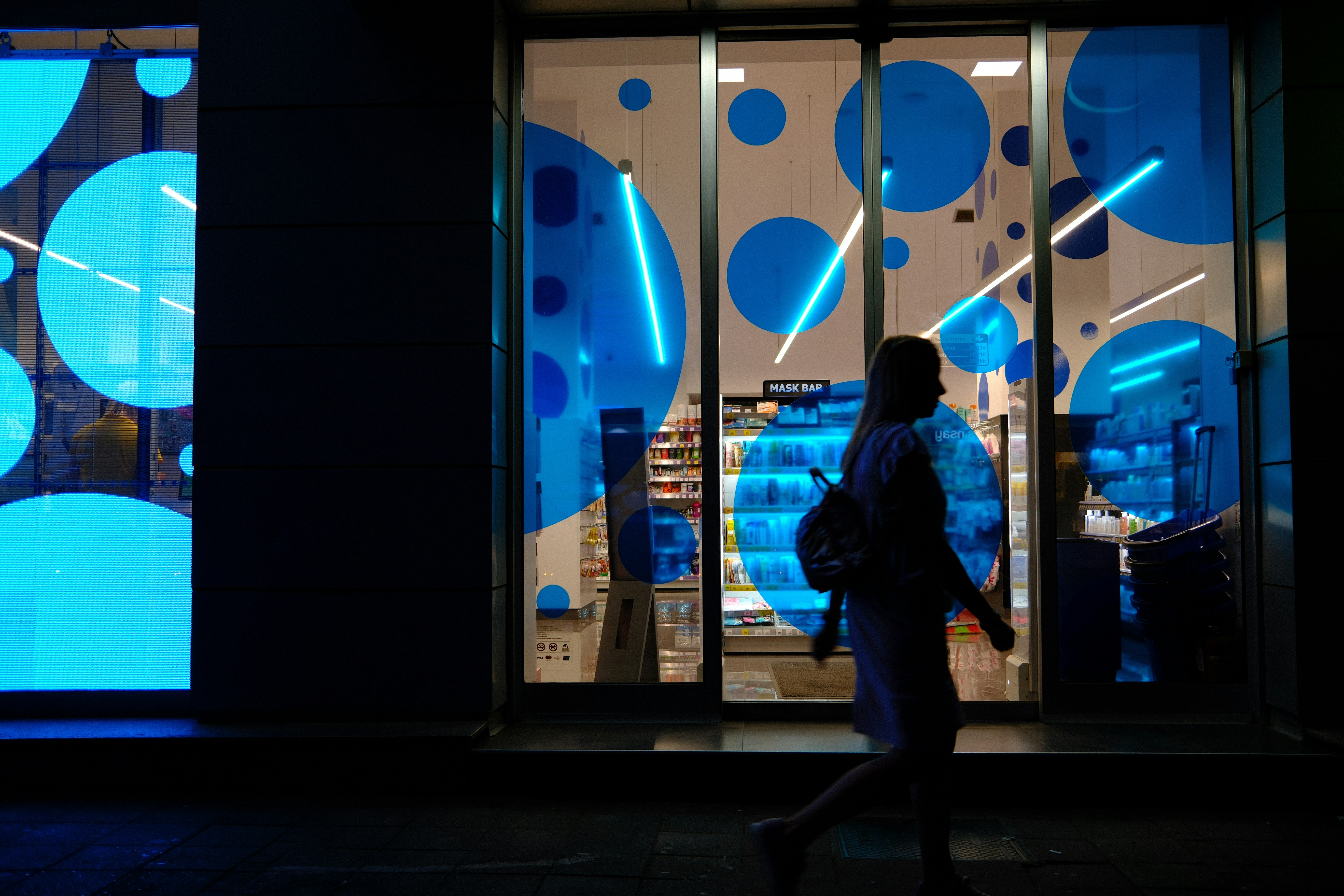 Blue Circles at the Glass: Night Walk Past a Neon Display