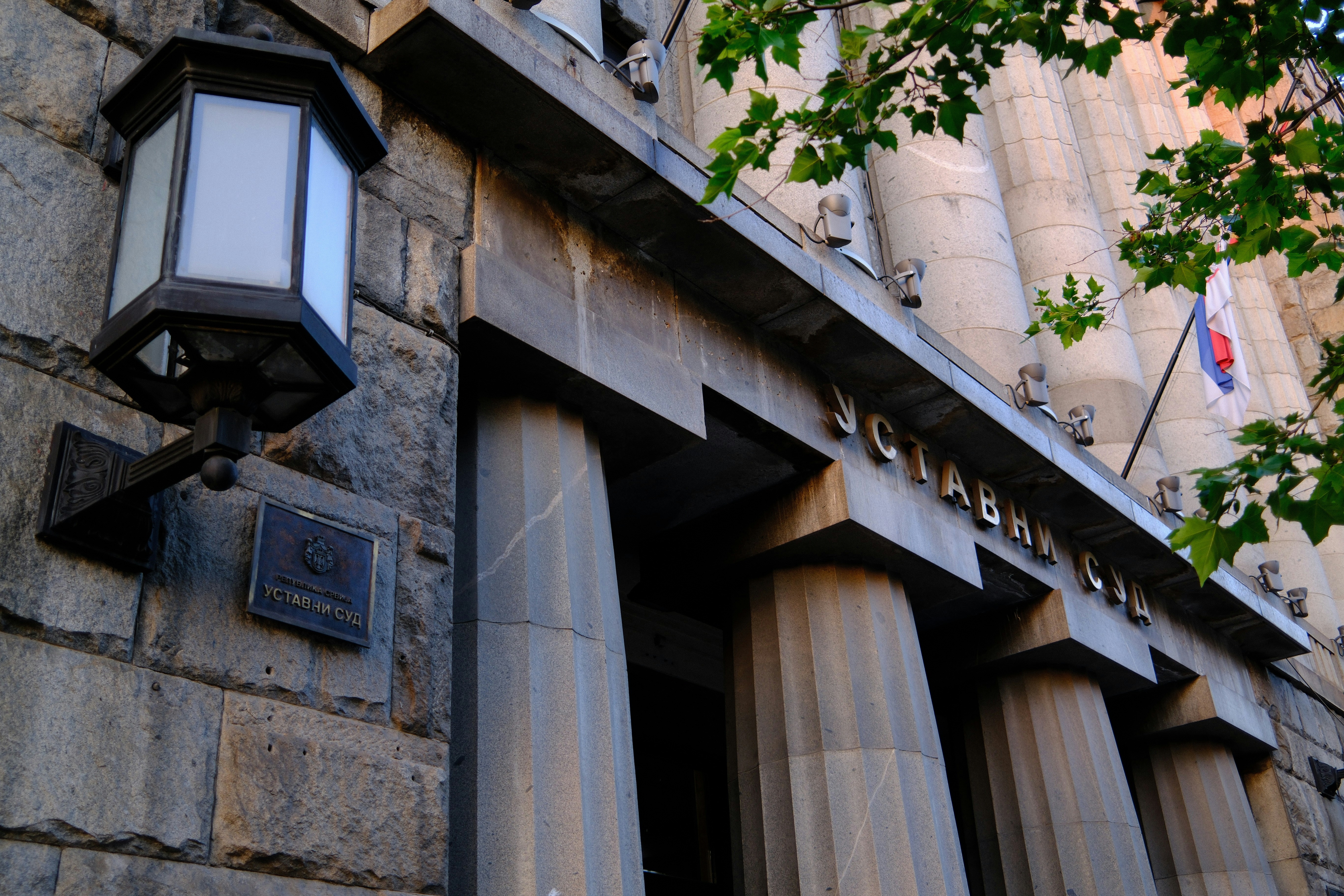 Stone building entrance with columns, a lantern, and carved text.