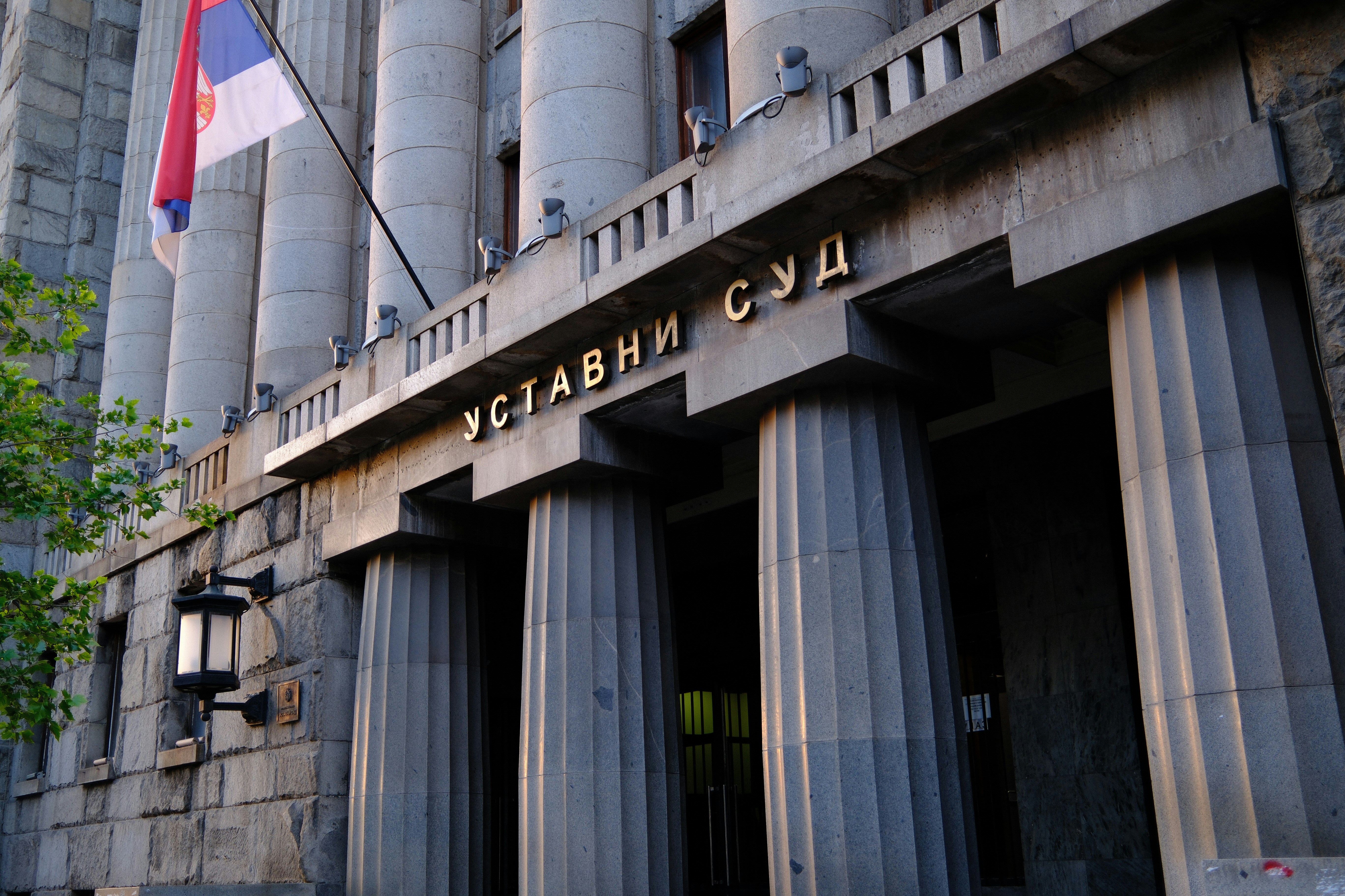 The constitutional court building with large columns and serbian flag.
