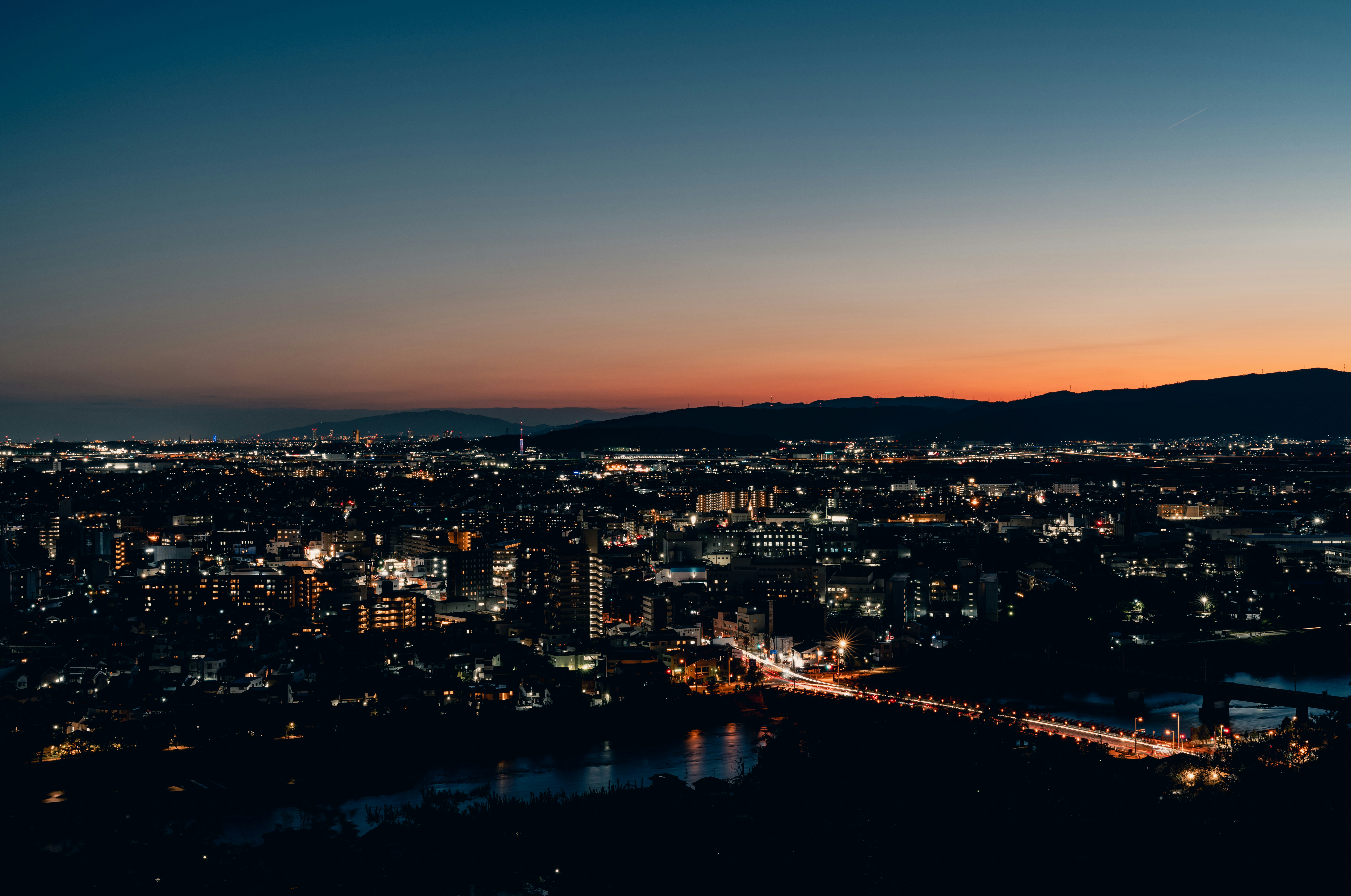 City lights illuminate a sprawling urban landscape at twilight.