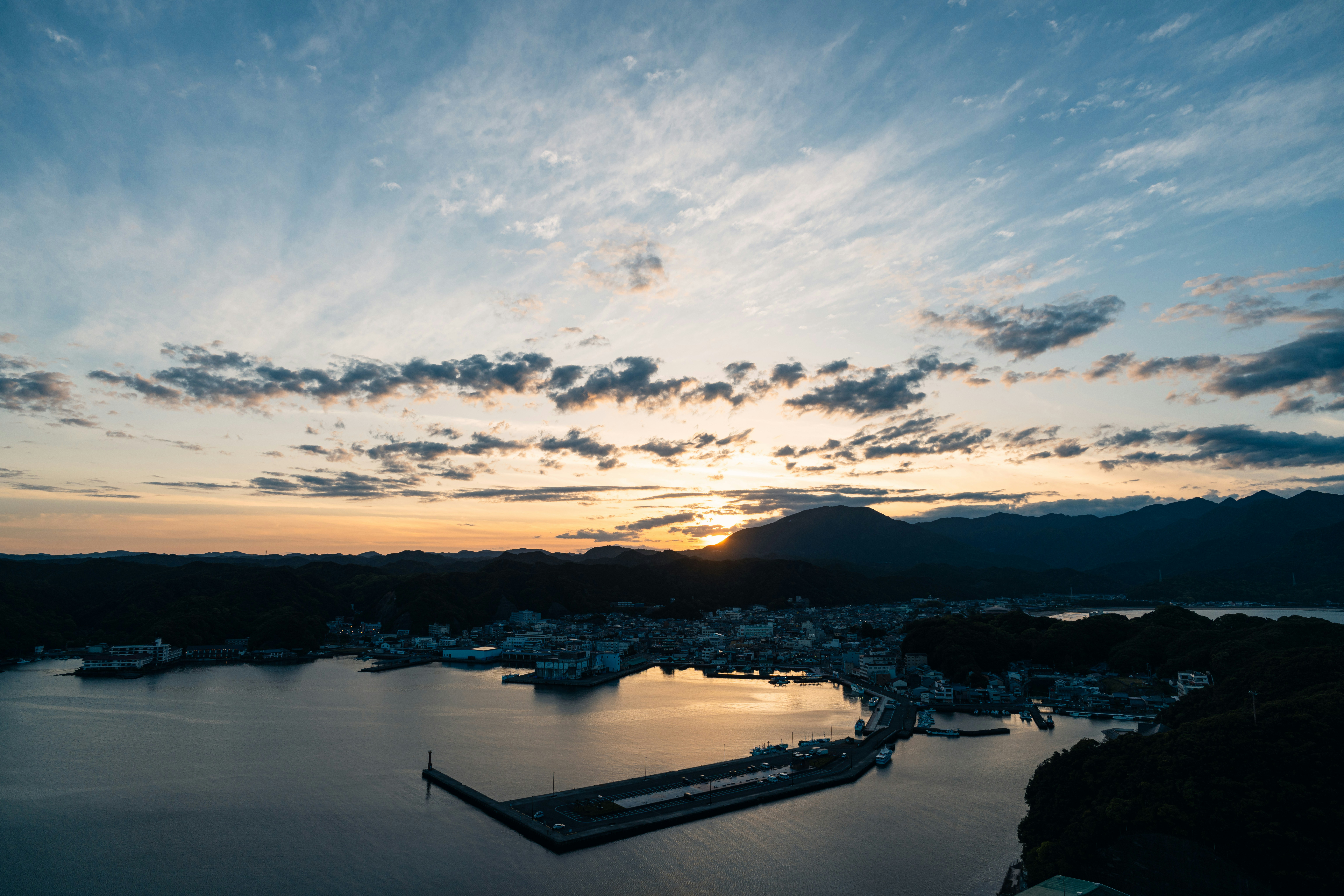 Dusk Harbor: Boats Quietly Rest as Mountains Embrace the Sunset